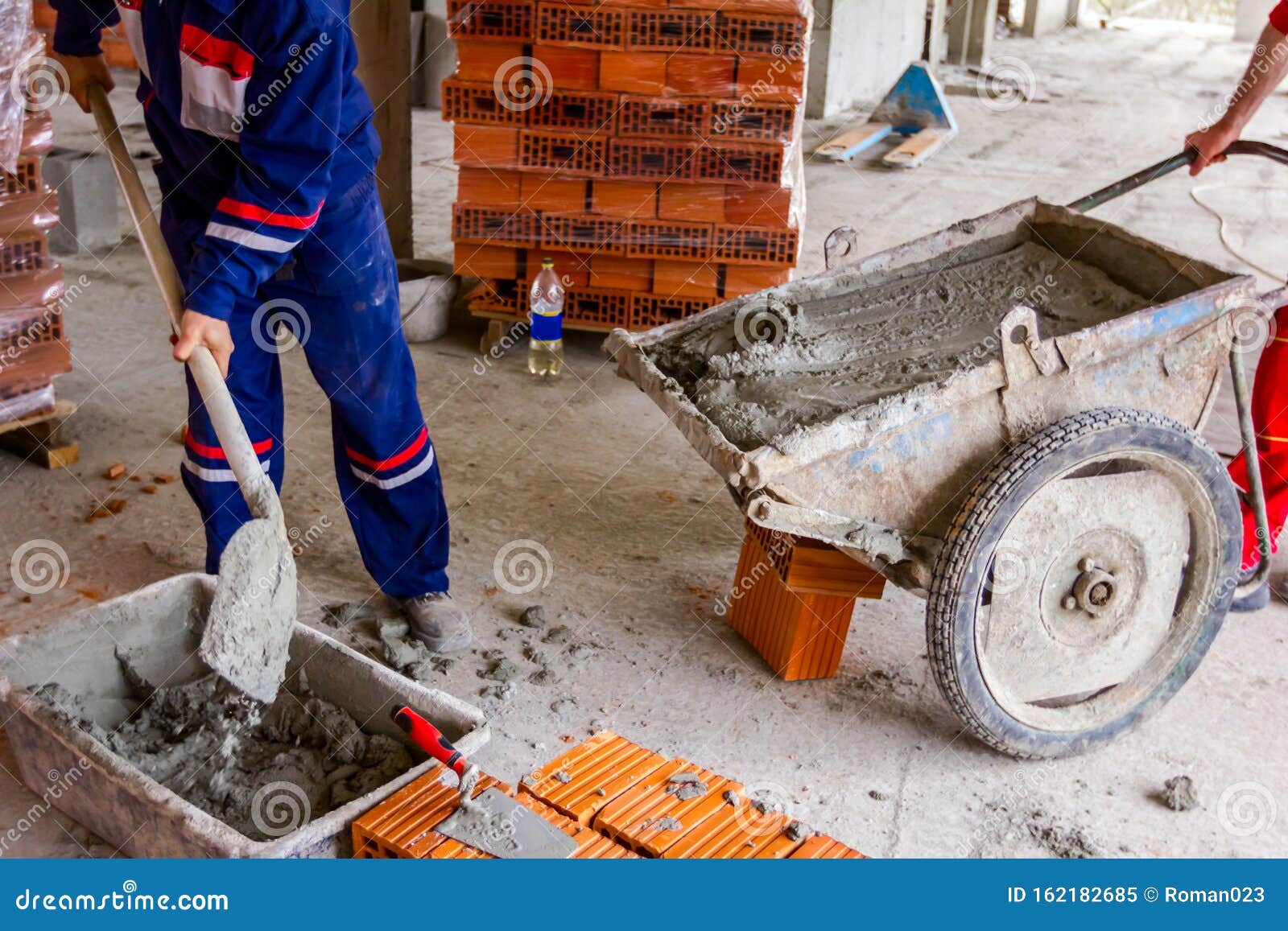 Worker is Using Shovel To Unload Wheelbarrow at Building Site Stock ...
