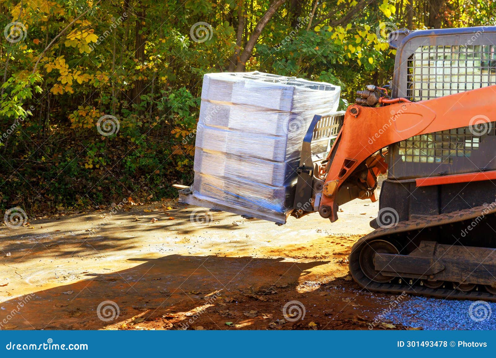 Worker is Using a Small Tractor To Unload Pallets of Concrete Blocks ...
