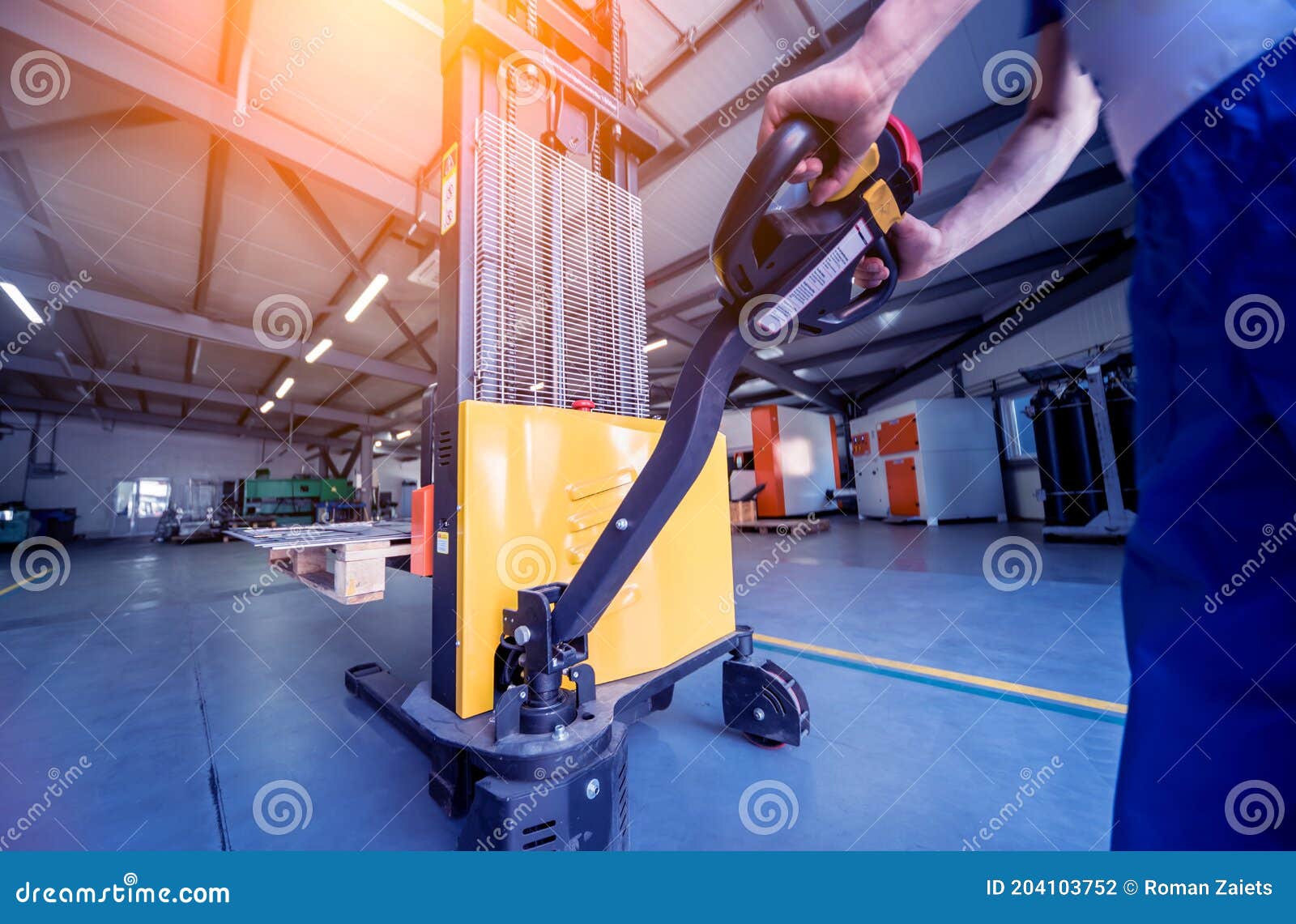 A Worker in a Warehouse Uses a Hand Pallet Stacker To Transport Pallets ...