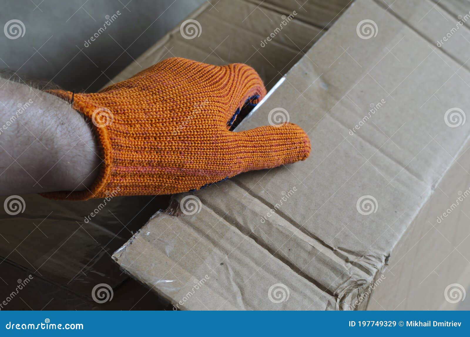 A Worker Wearing Protective Gloves Opens a Cardboard Box Stock Image ...