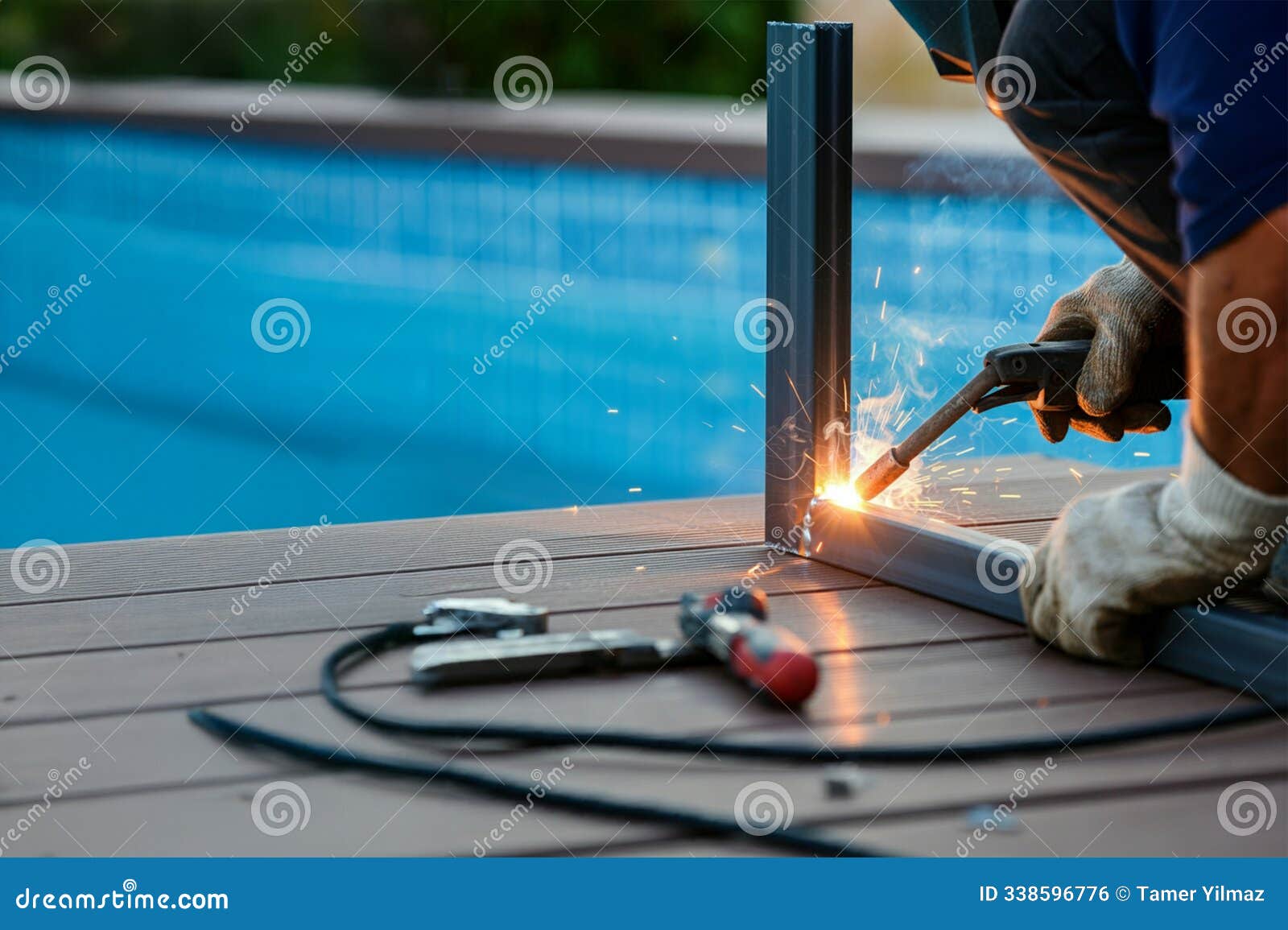 A Worker Working by the Pool Does Welding Work. Blue Colored Pool in ...