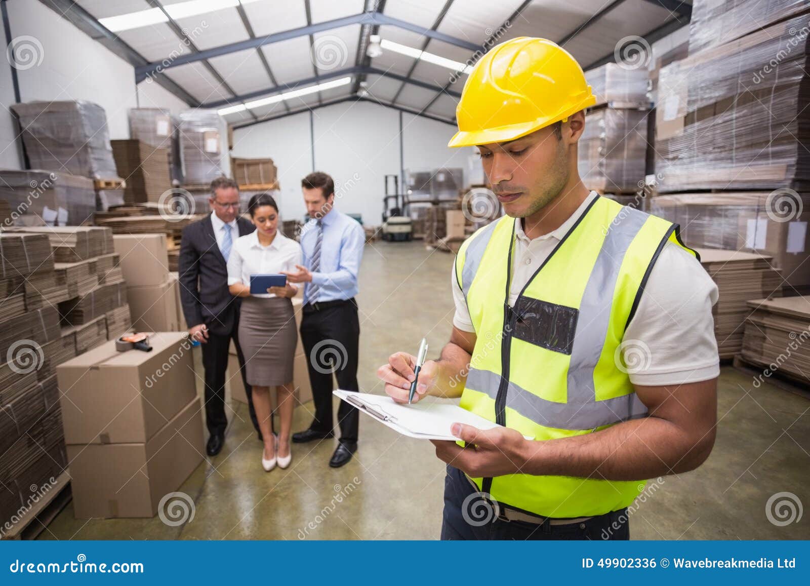 Worker Writing on Clipboard in Front of His Colleagues Stock Photo ...