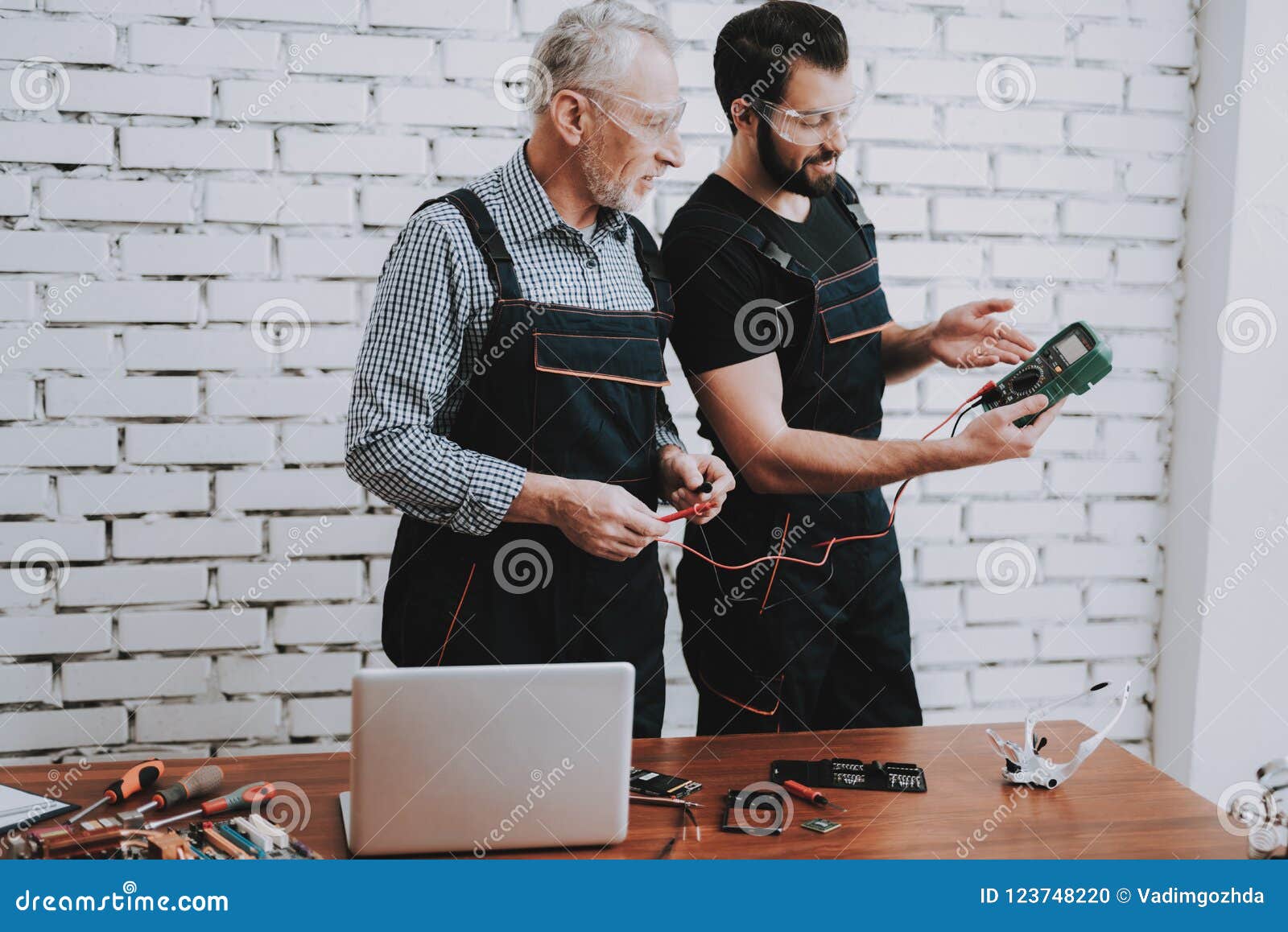 Workers Checking Device in Hands in Repair Shop. Stock Photo - Image of ...