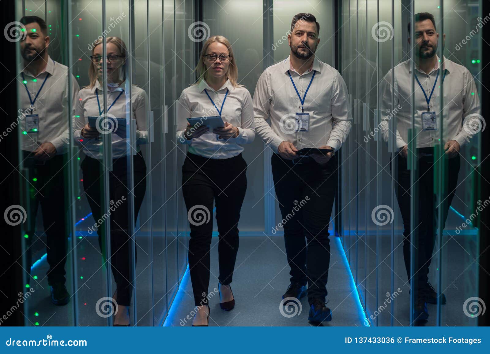 Workers in a Data Center Walking between Rows of Server Racks Stock ...