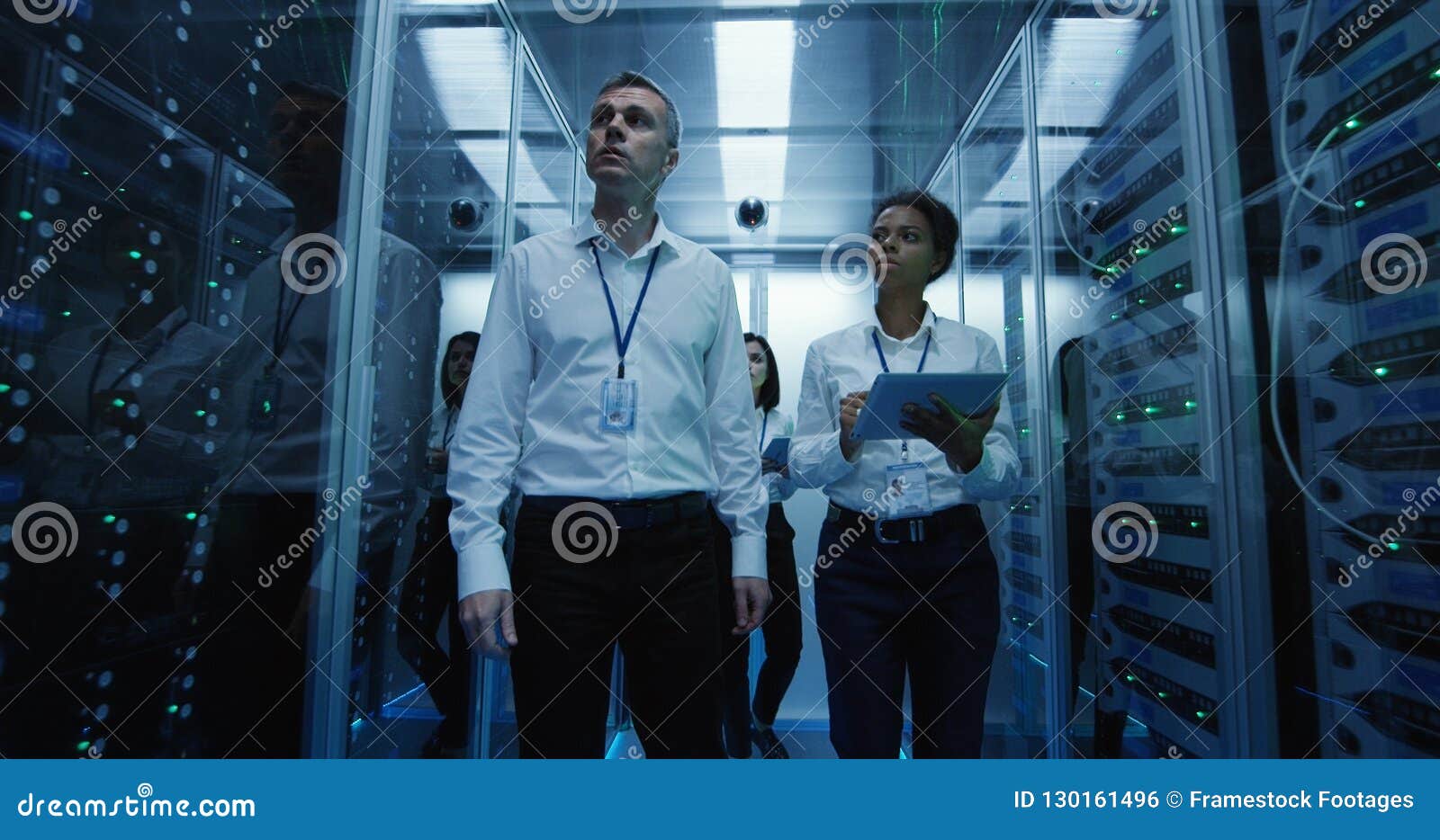 Workers in a Data Center Walking between Rows of Server Racks Stock ...