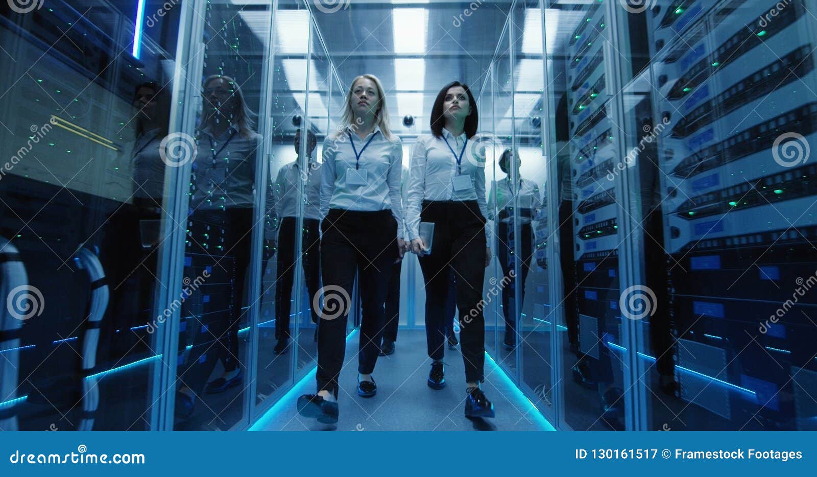 Workers in a Data Center Walking between Rows of Server Racks Stock ...