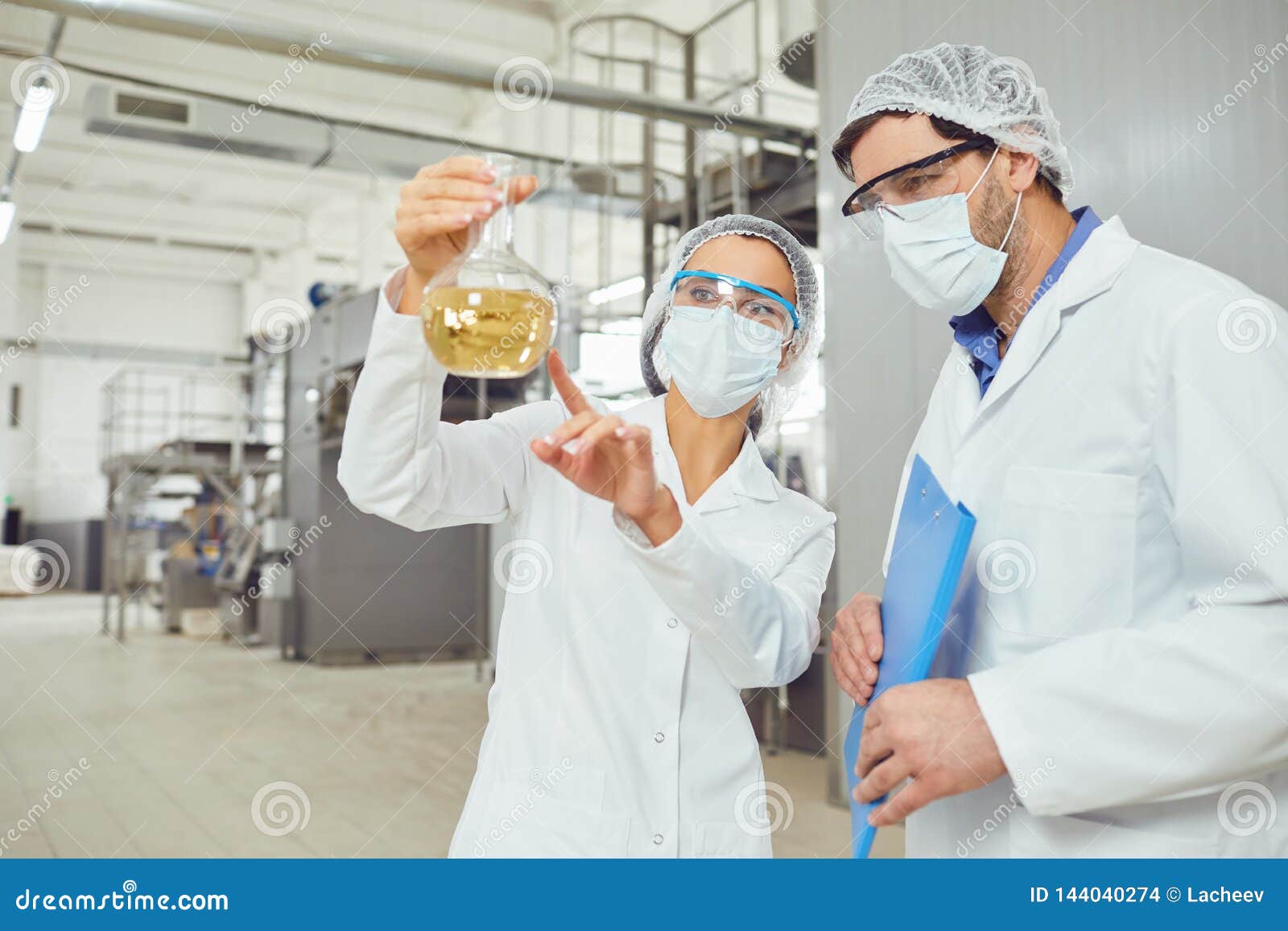 Workers in Masks and Coats Look at the Liquid in the Flask at Work ...