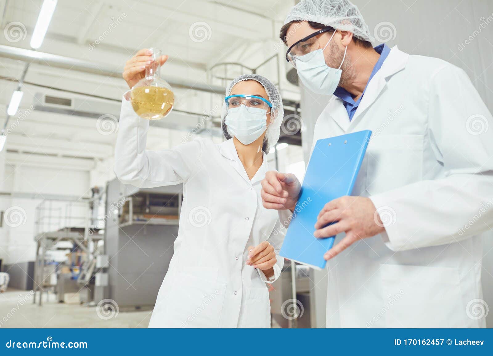 Workers in Masks and Coats Look at the Liquid in the Flask at Work ...