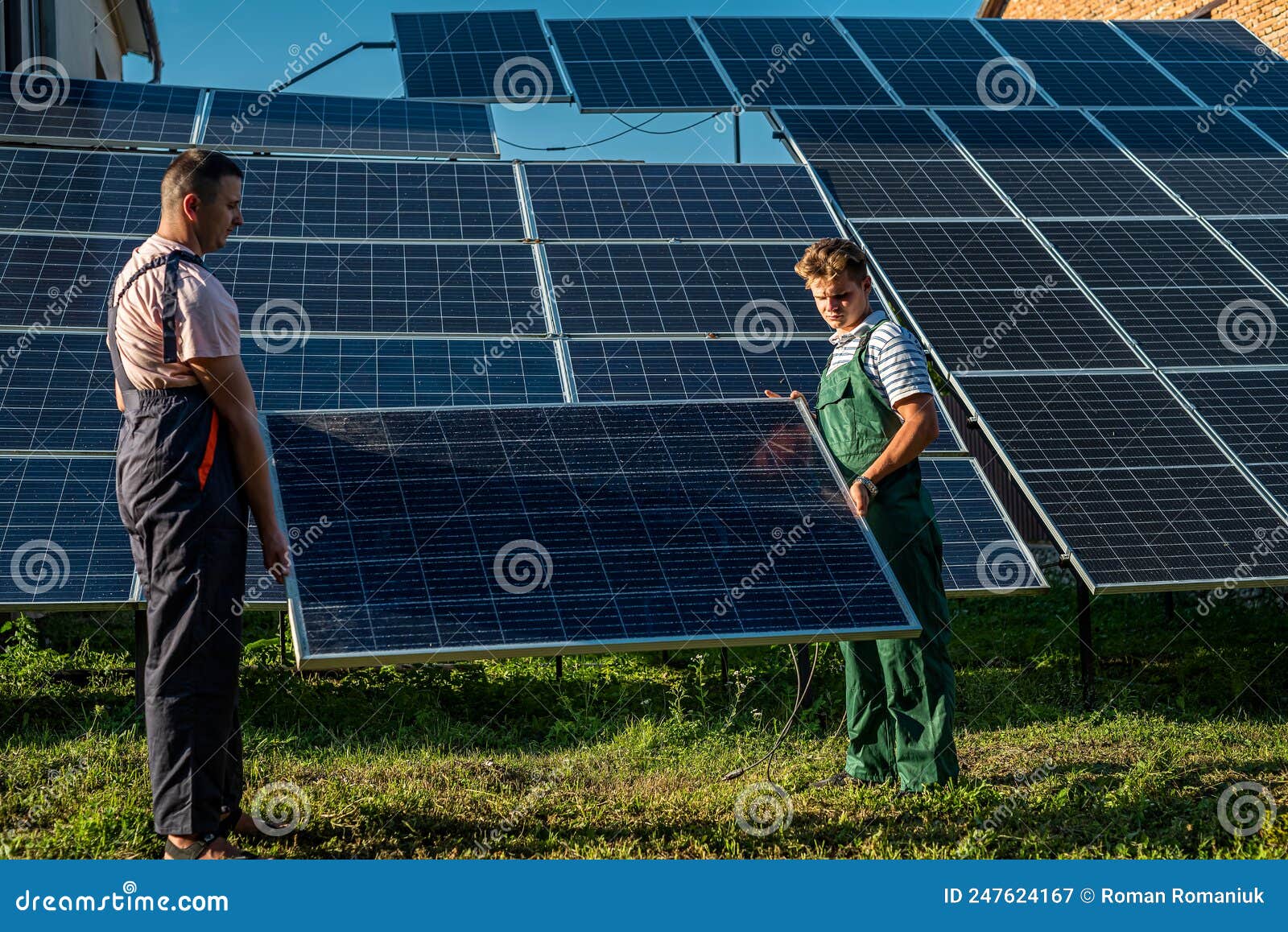 Workers in Protective Uniform Carrying Solar Panel for Installation at ...