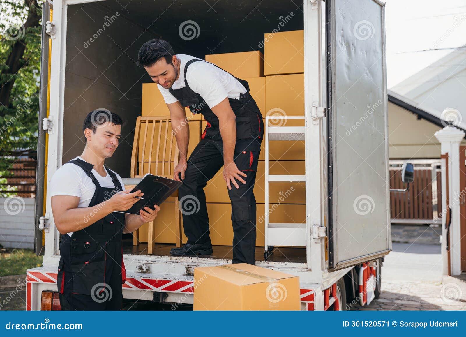 Workers in Uniform Unload Boxes Inspecting Shipment with a Clipboard ...