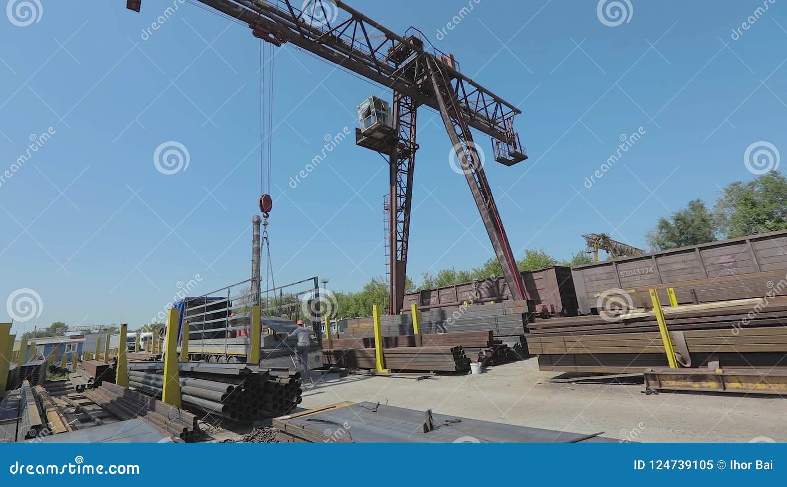 Workers Unload a Sheet of Metal in a Truck Standing Under a Gantry ...