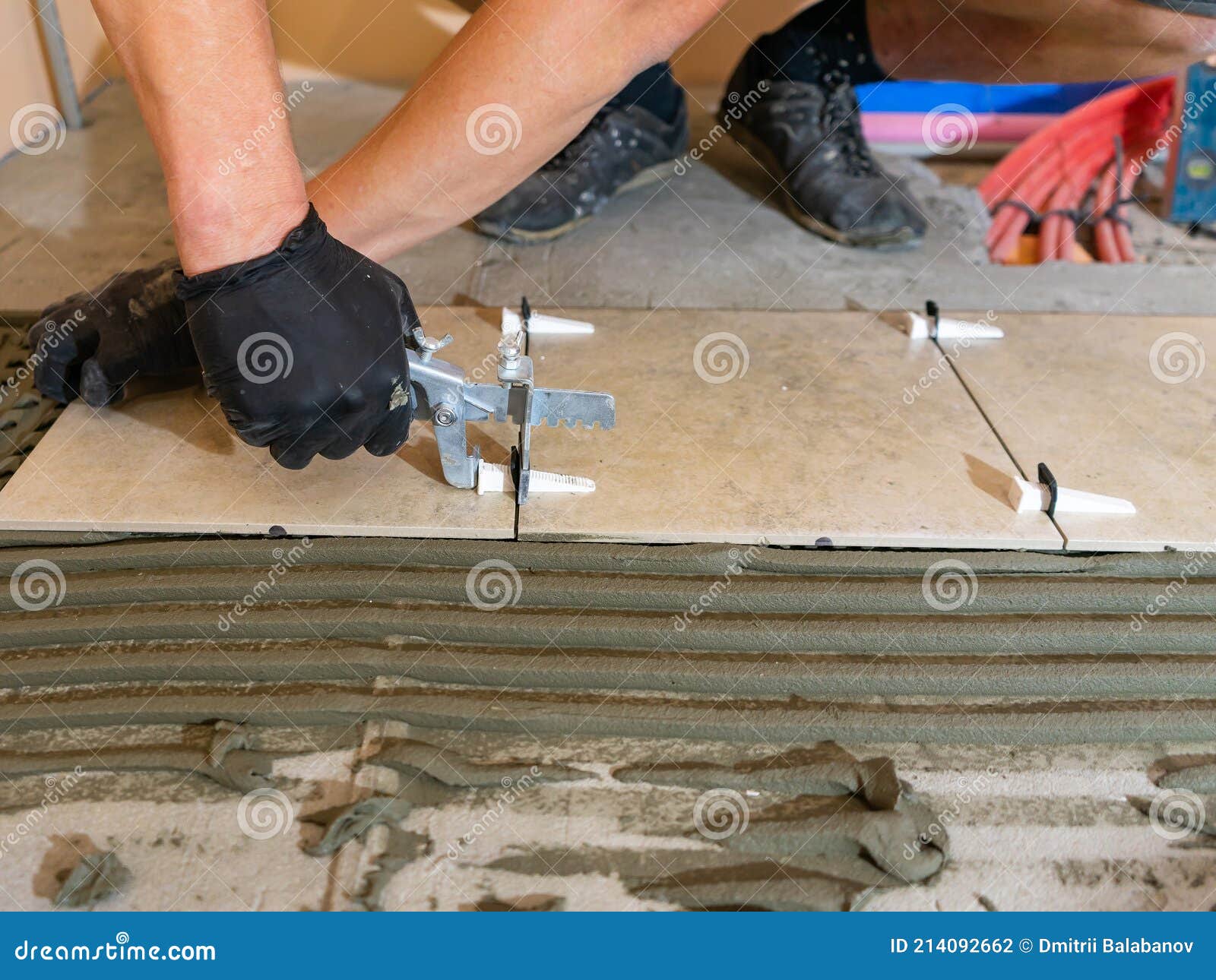 Workers are Using Plastic Clamps and Wedges To Leveling the Ceramic Tile on the Floor. Tile ...