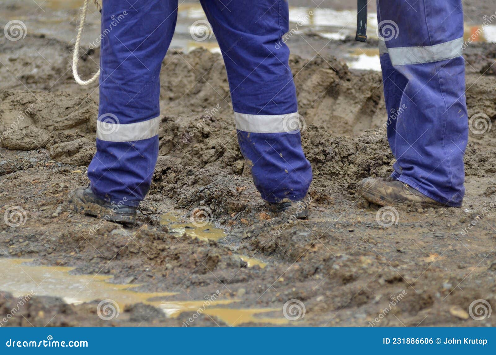 Workers Wearing Overalls and Workboots Stand in a Muddy Environment ...