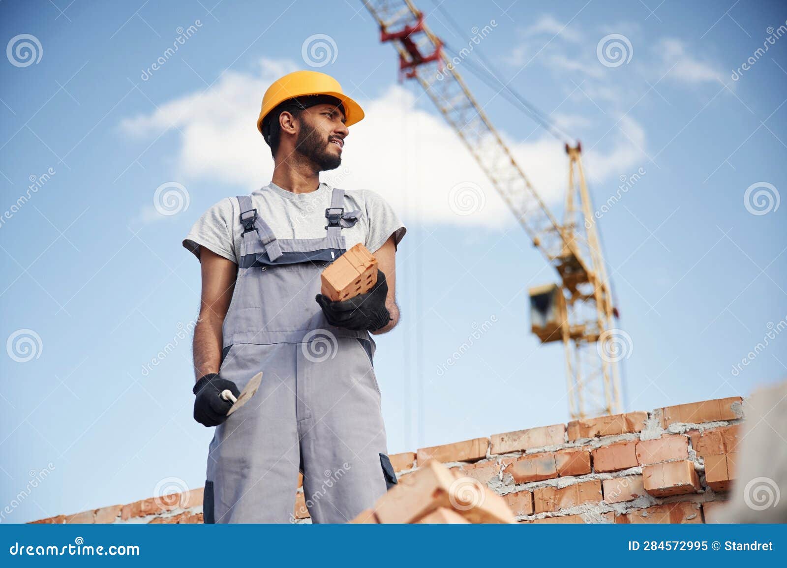 Showing and Holding Little Shovel and Brick. Handsome Indian Man is on ...