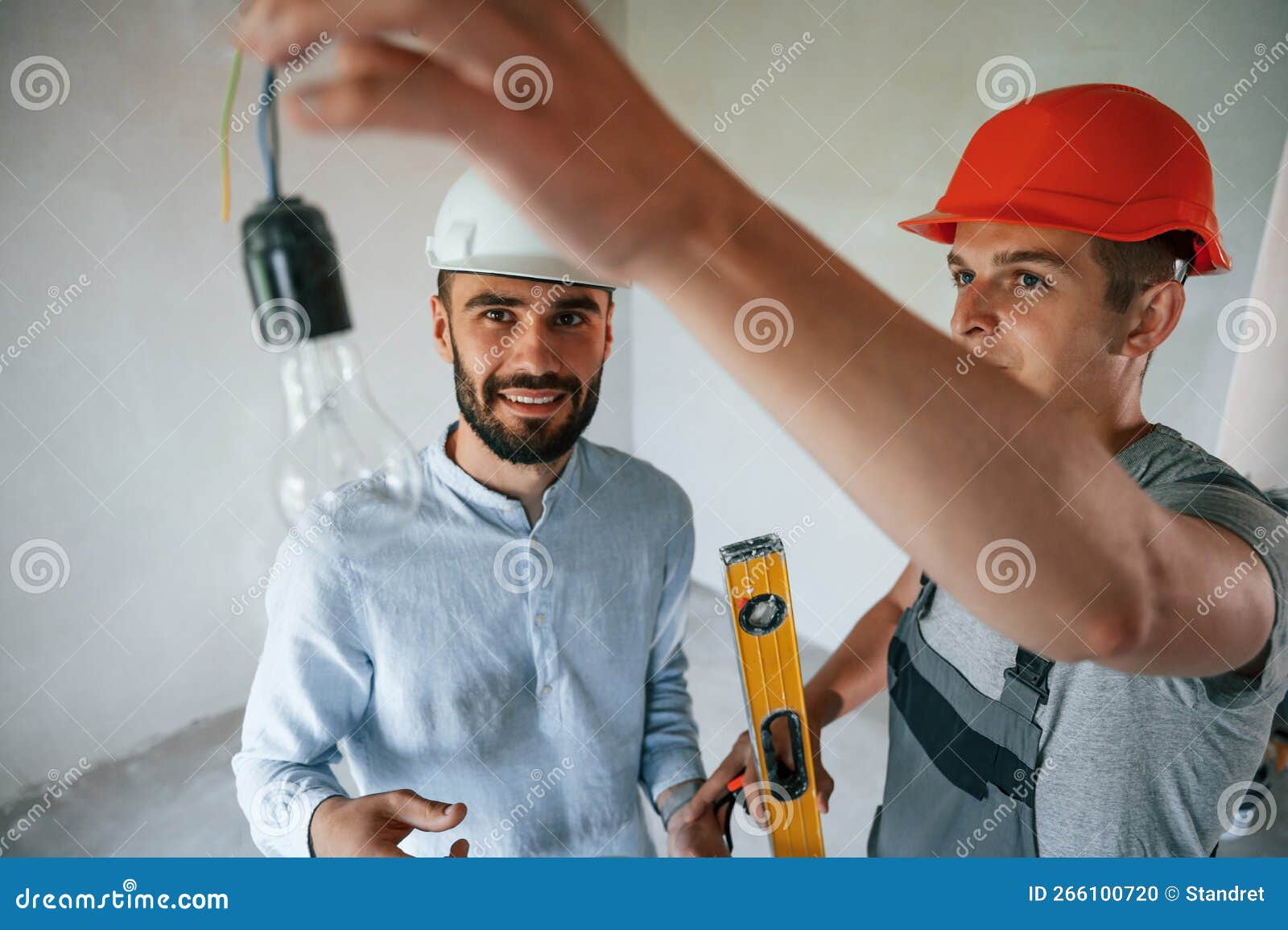 Working with Light Bulb. Two Men is Making Repairs in the Apartment ...