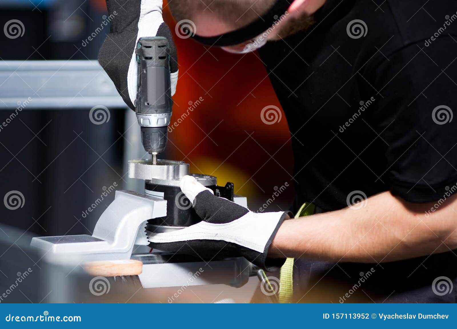Working Man in a T-shirt at a Workbench Working with a Screwdriver ...