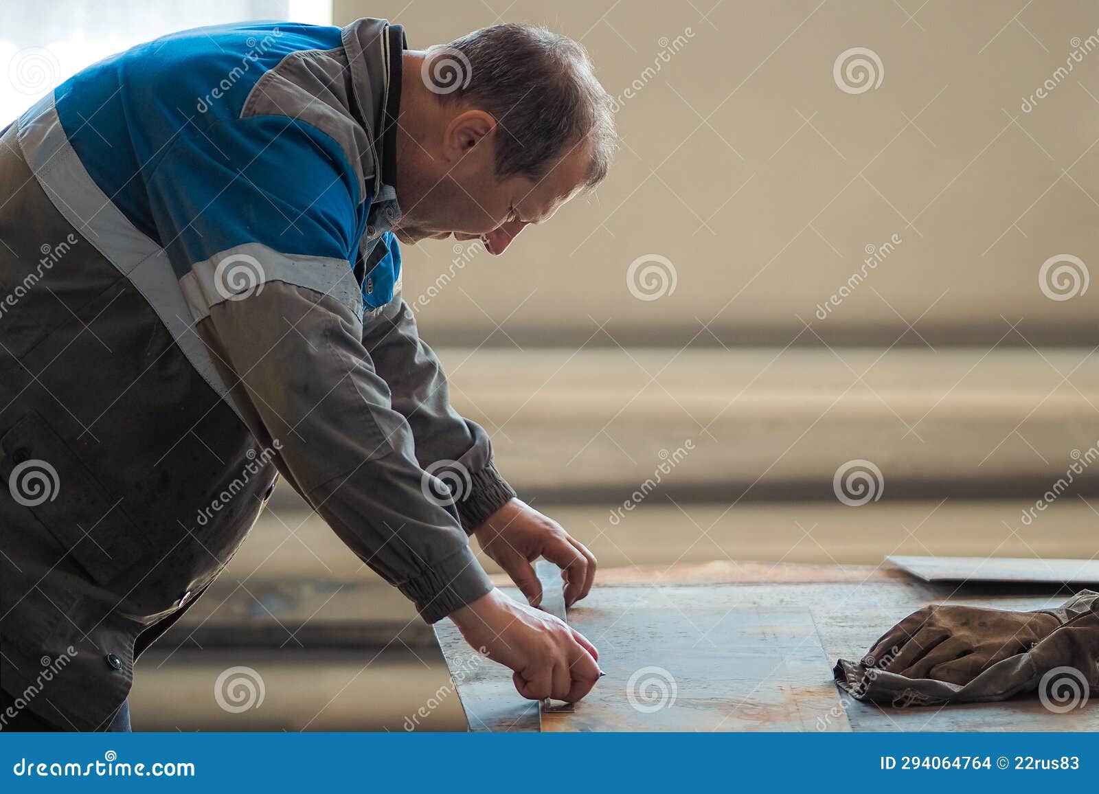 Working Man Works at Workbench in Workshop. Man in Overalls Measures ...