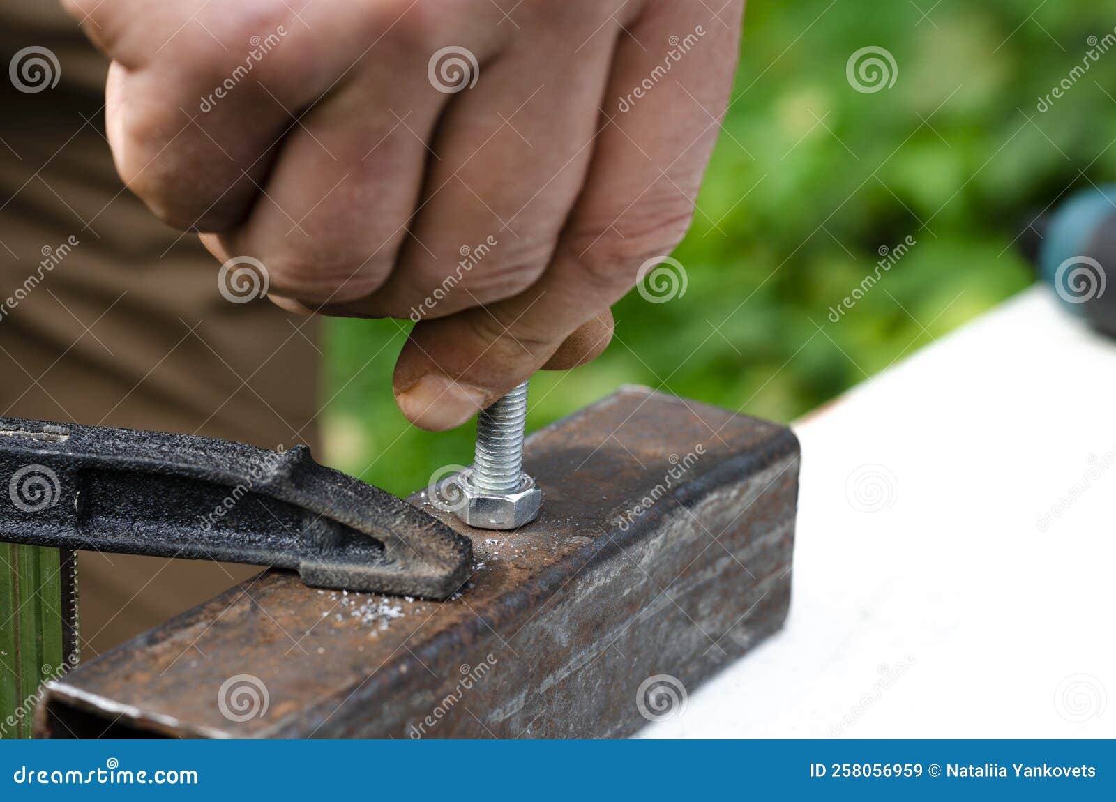 Working with Metal. a Man& X27;s Hand Screws a Bolt into a Metal Nut ...