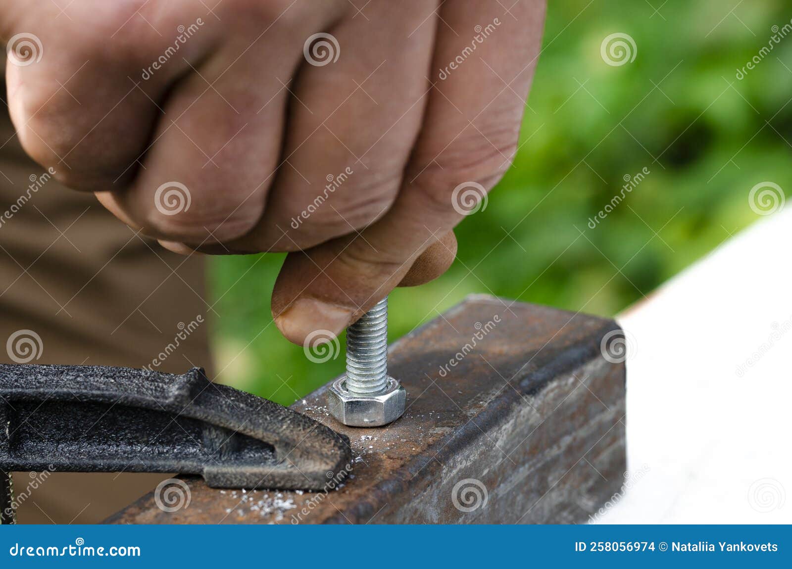 Working with Metal. a Man& X27;s Hand Screws a Bolt into a Metal Nut ...