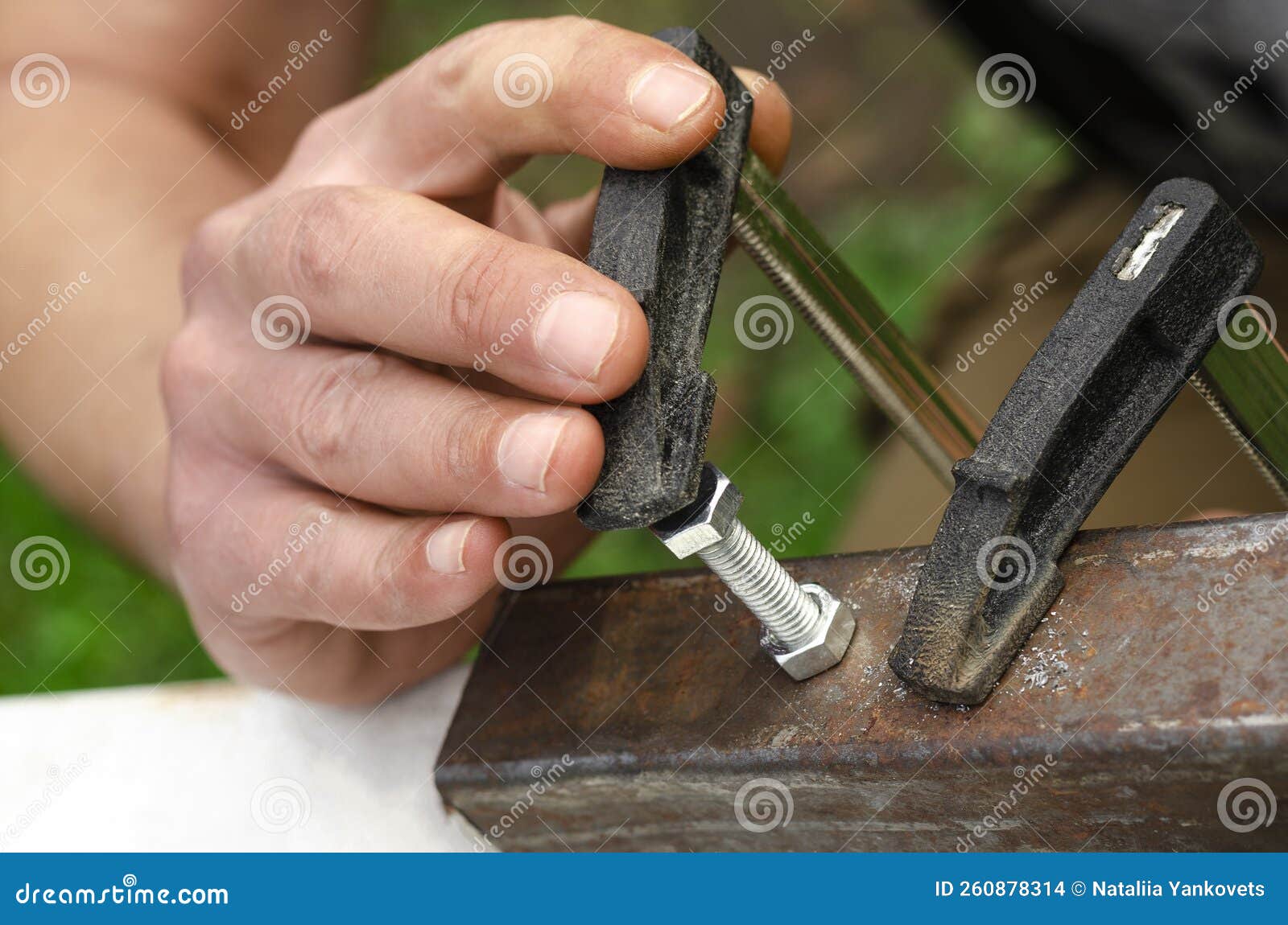 Working with Metal. a Man& X27;s Hand Screws a Bolt into a Metal Nut ...