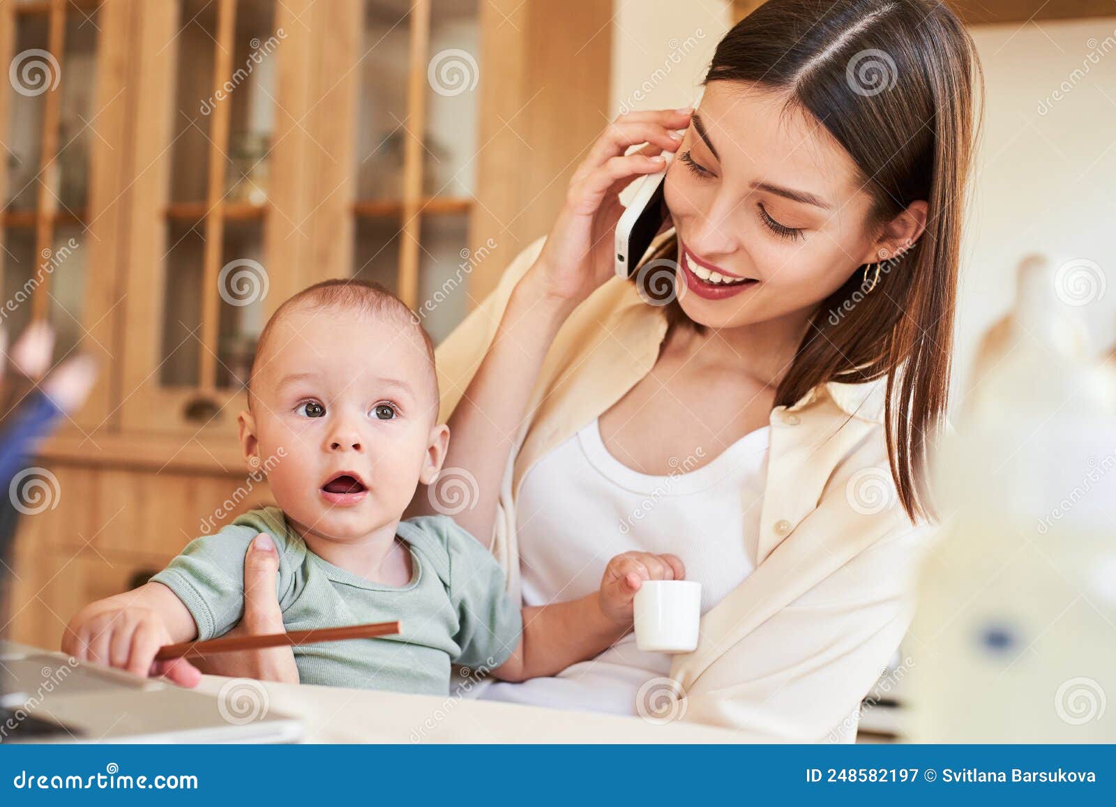 A Working Mom on the Phone with Her Clients with Her Baby on Her Lap ...