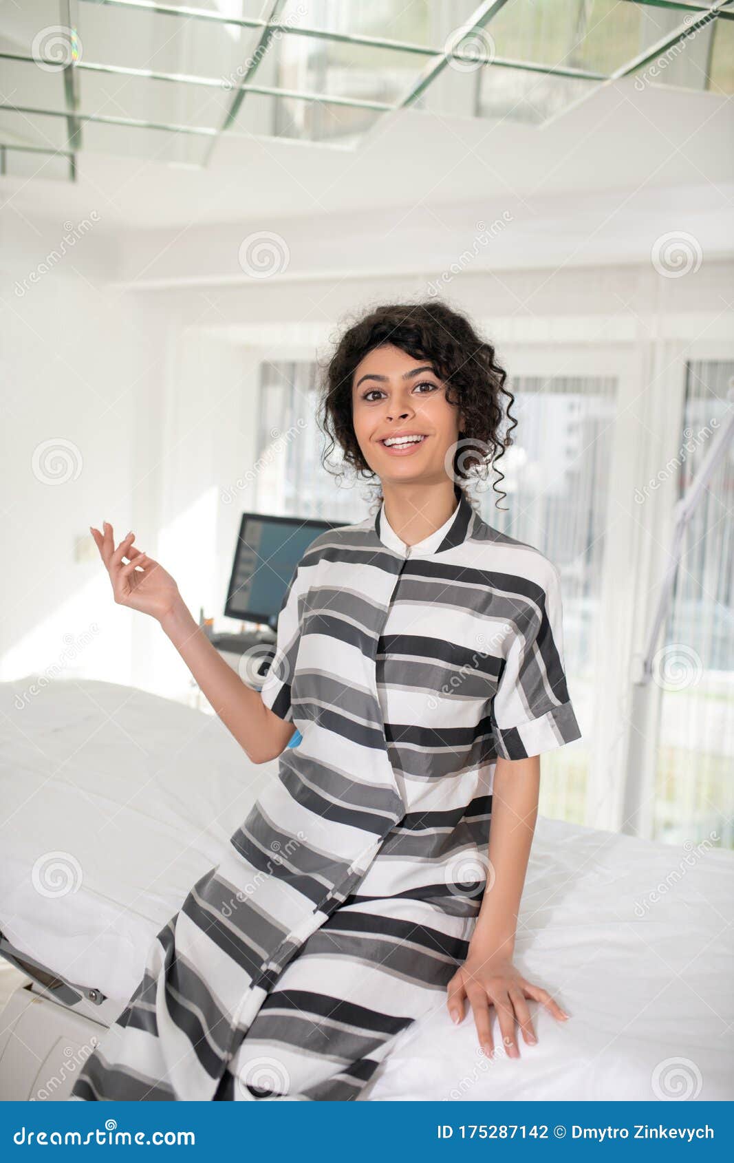 Dark Haired Beautiful Woman In Striped Shirt Sitting On The Couch Stock