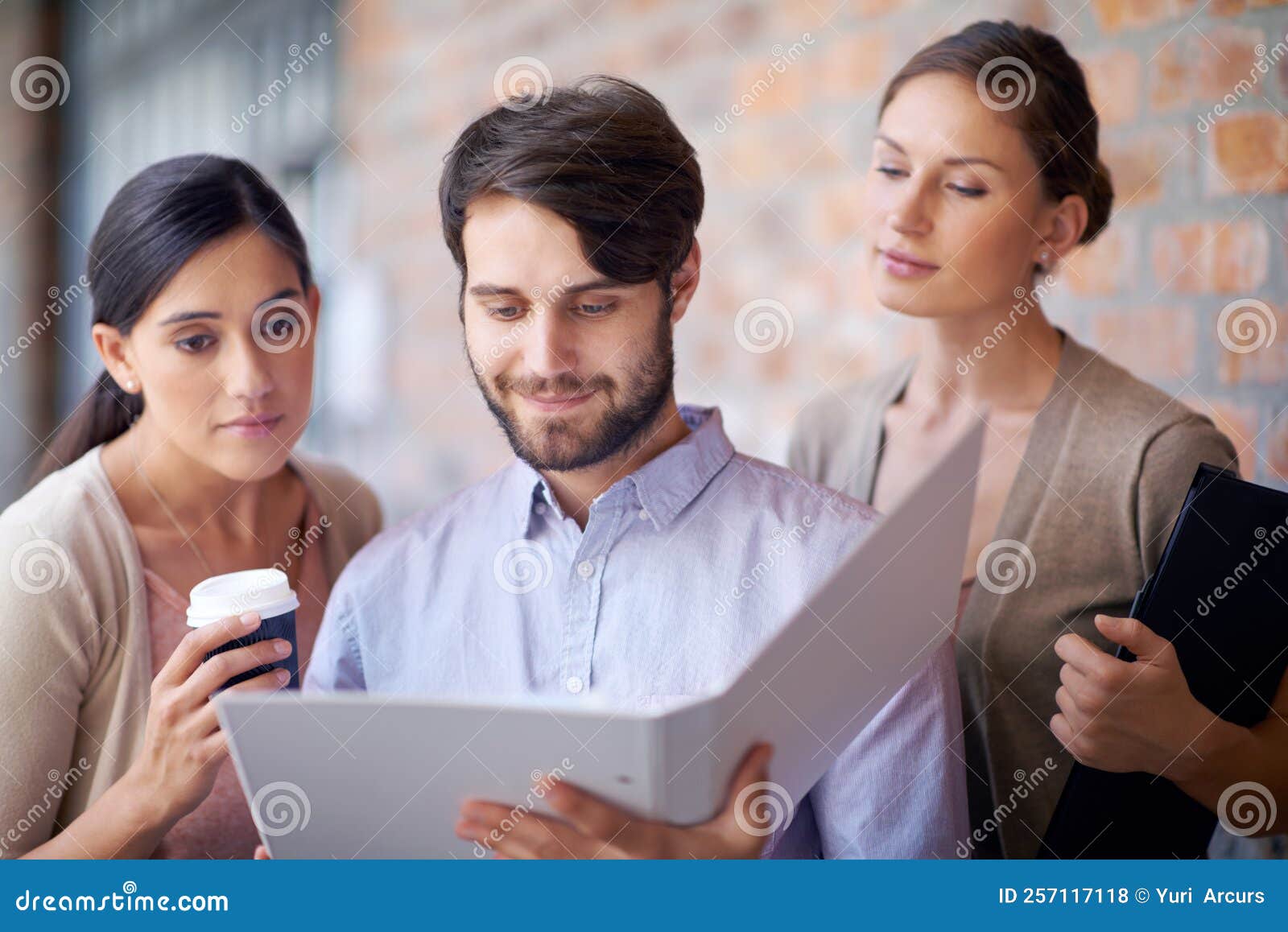 Working through Their Work Files. Three Young Colleagues in Their ...