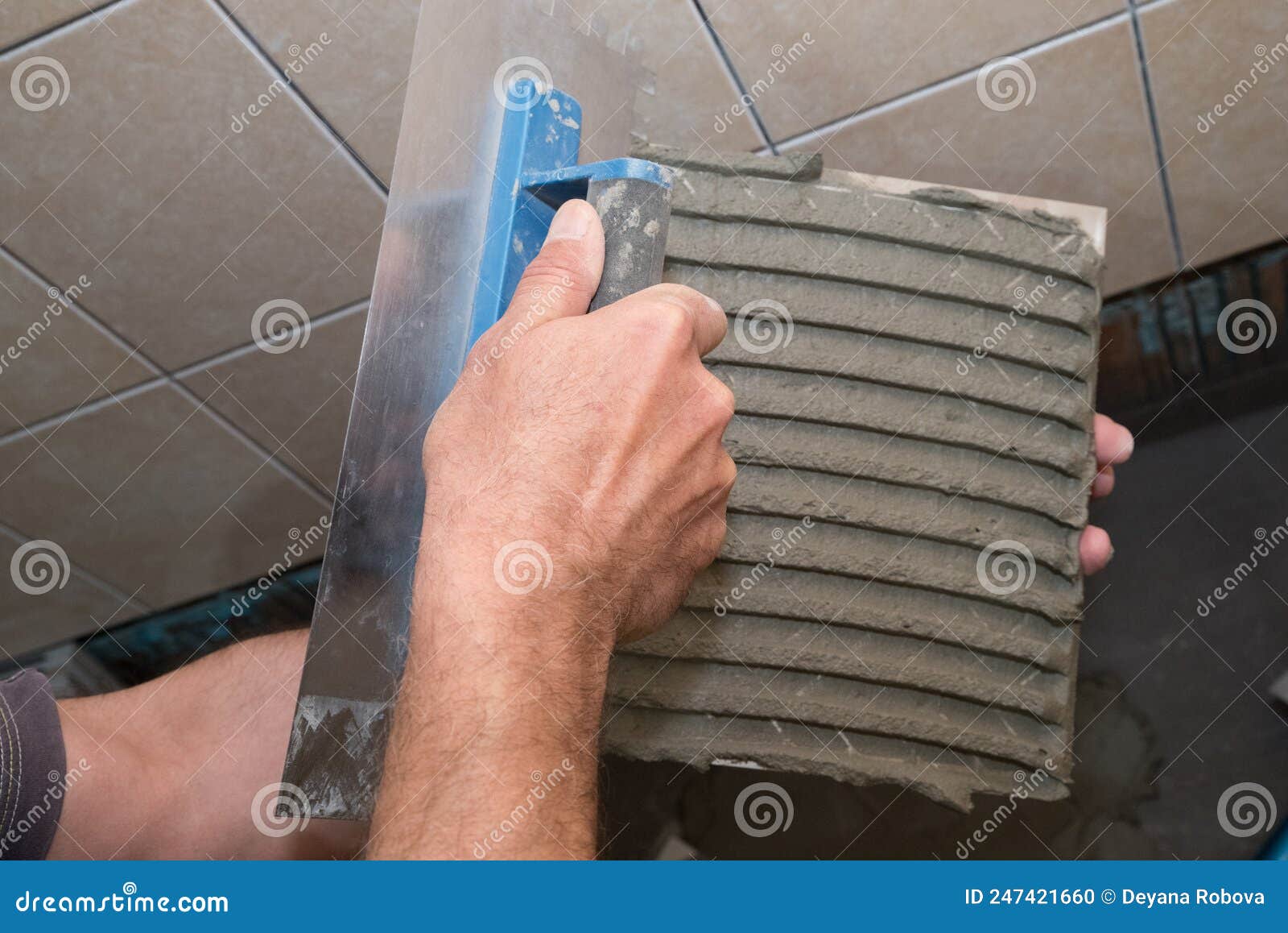 The Working Tiler Applies Glue on the Tile with a Notched Trowel before ...