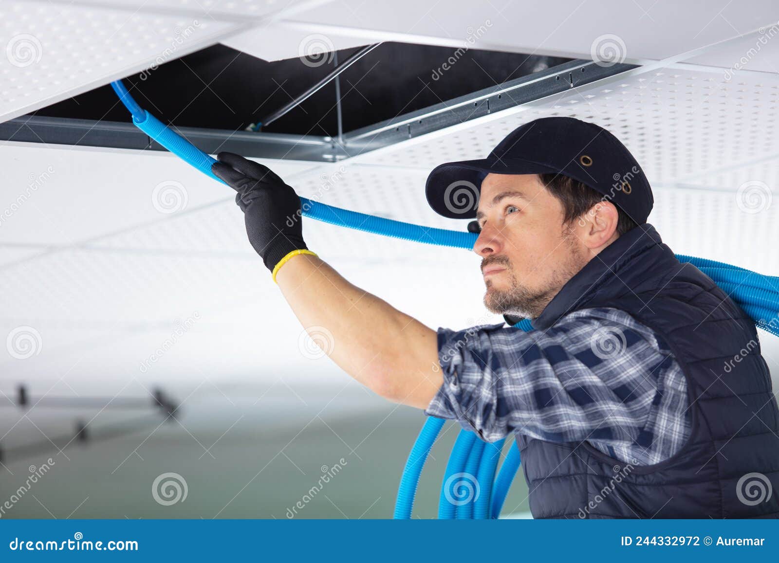 Workman Inserting Blue Pipework through Ceiling Panel Stock Photo ...