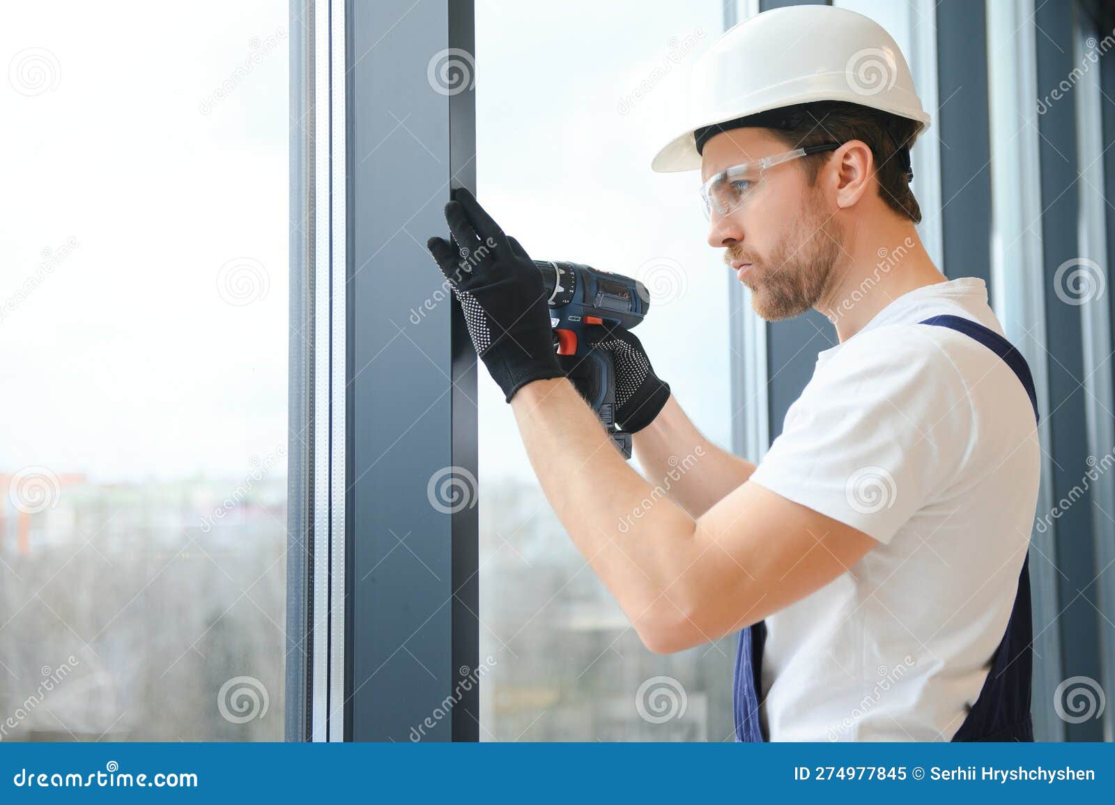 Workman in Overalls Installing or Adjusting Plastic Windows in the ...