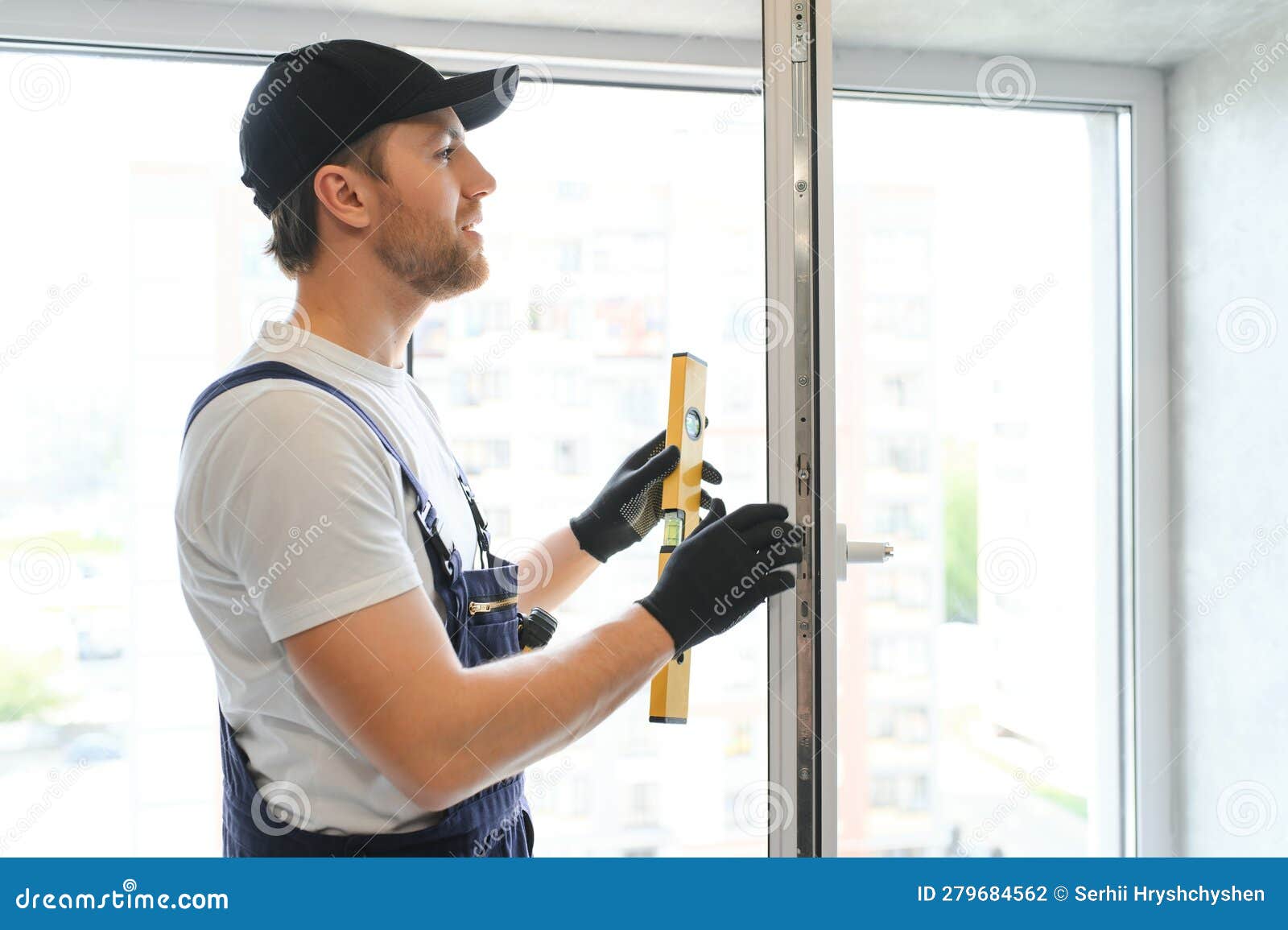 Workman in Overalls Installing or Adjusting Plastic Windows in the Living Room at Home Stock ...