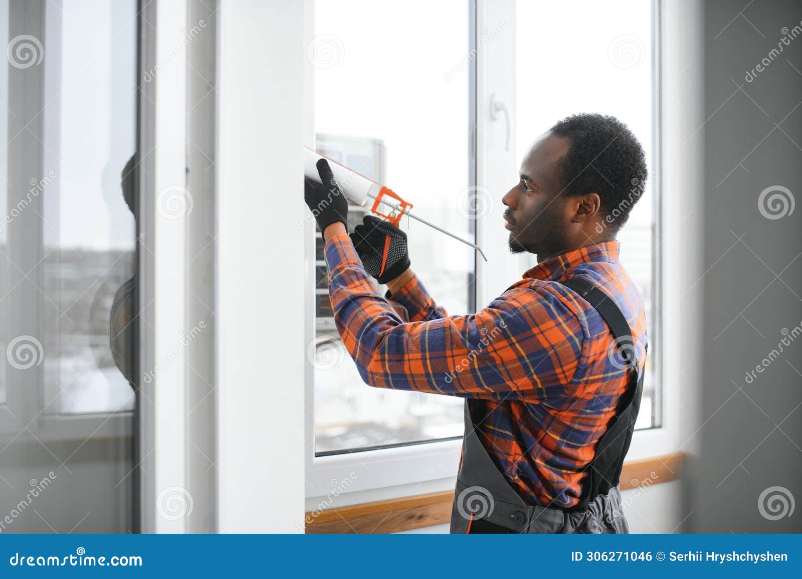 Workman in Overalls Installing or Adjusting Plastic Windows in the ...