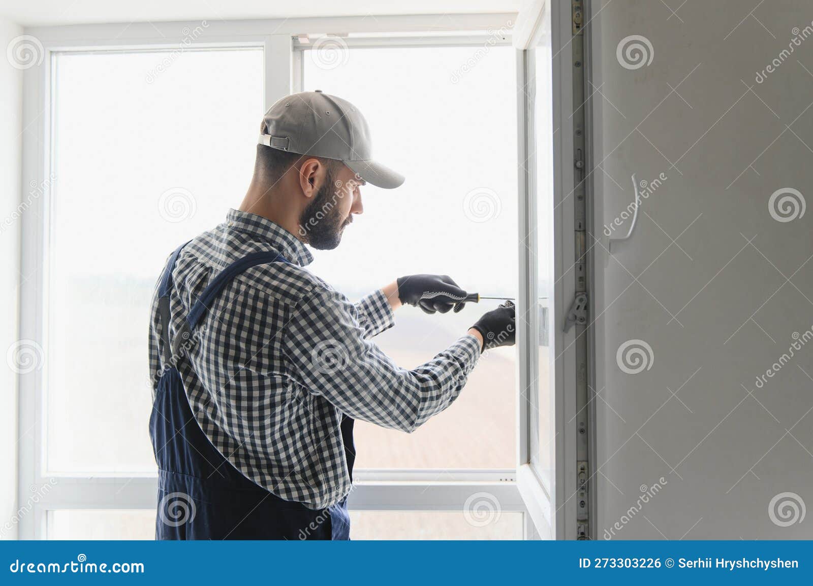 Workman in Overalls Installing or Adjusting Plastic Windows in the ...
