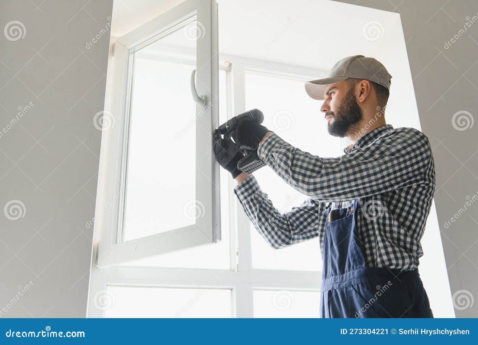 Workman in Overalls Installing or Adjusting Plastic Windows in the ...