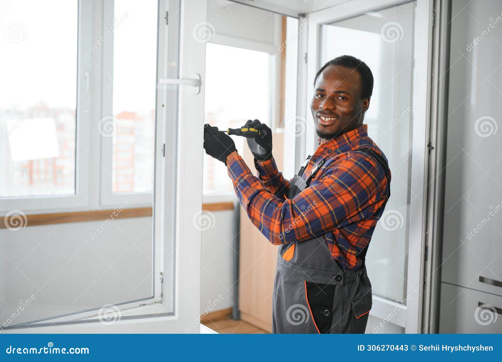 Workman in Overalls Installing or Adjusting Plastic Windows in the ...