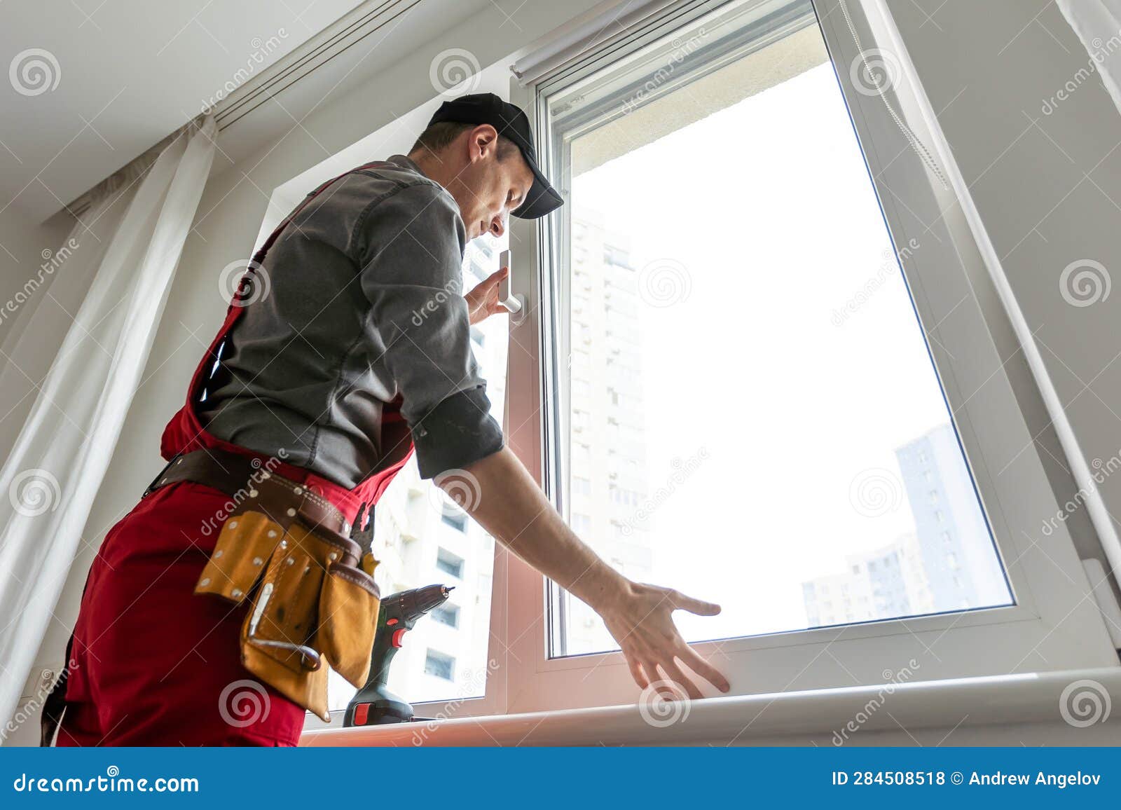 Workman in Overalls Installing or Adjusting Plastic Windows in the Living Room at Home Stock ...
