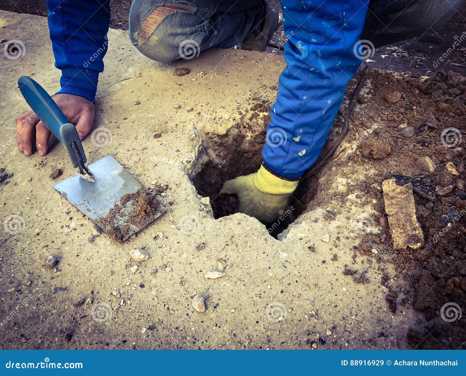 A Workman Reaching into a Hole he`s Been Digging To Pull Out Earth and ...