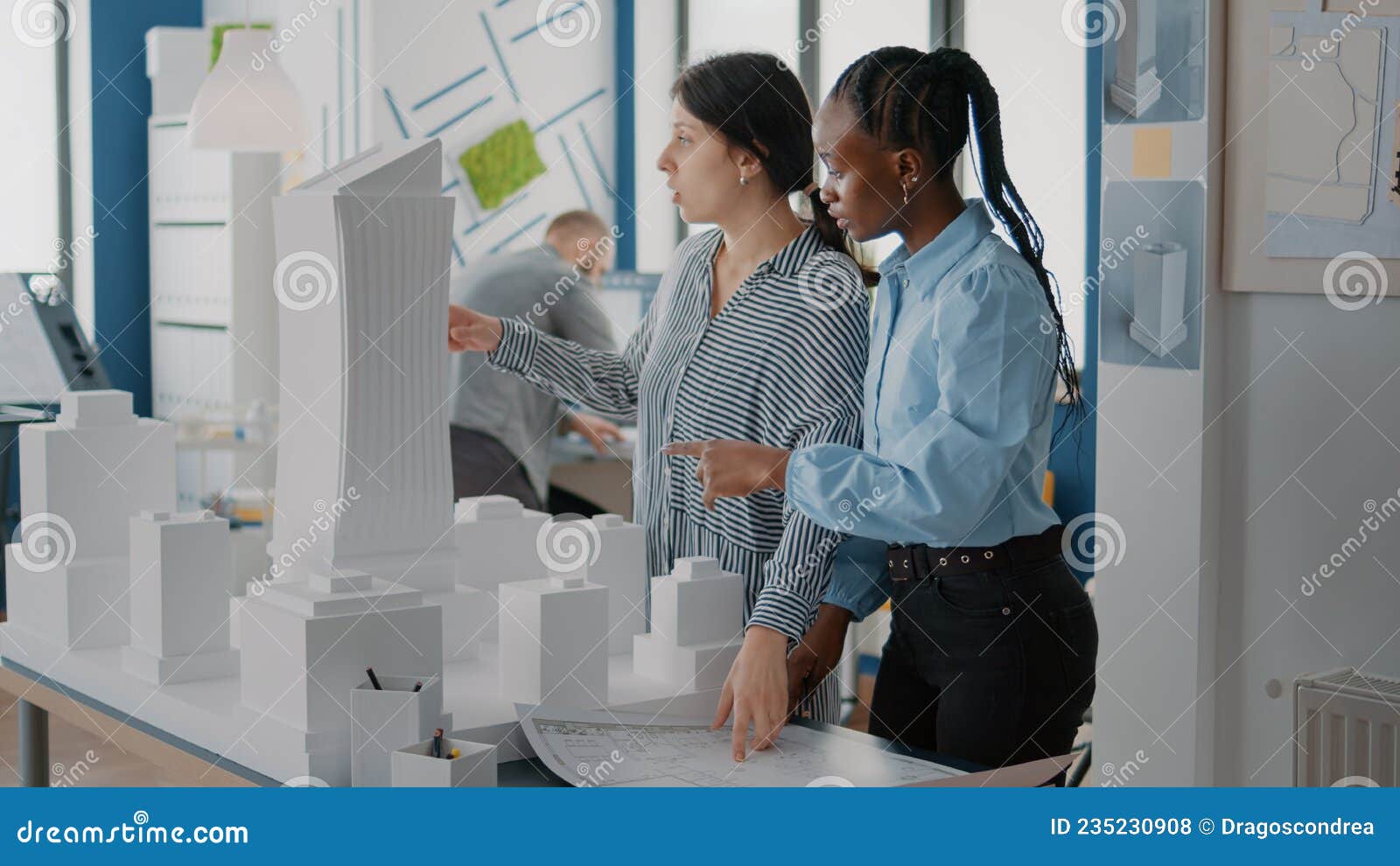 Workmates Analyzing Blueprints Plan and Building Model on Table ...
