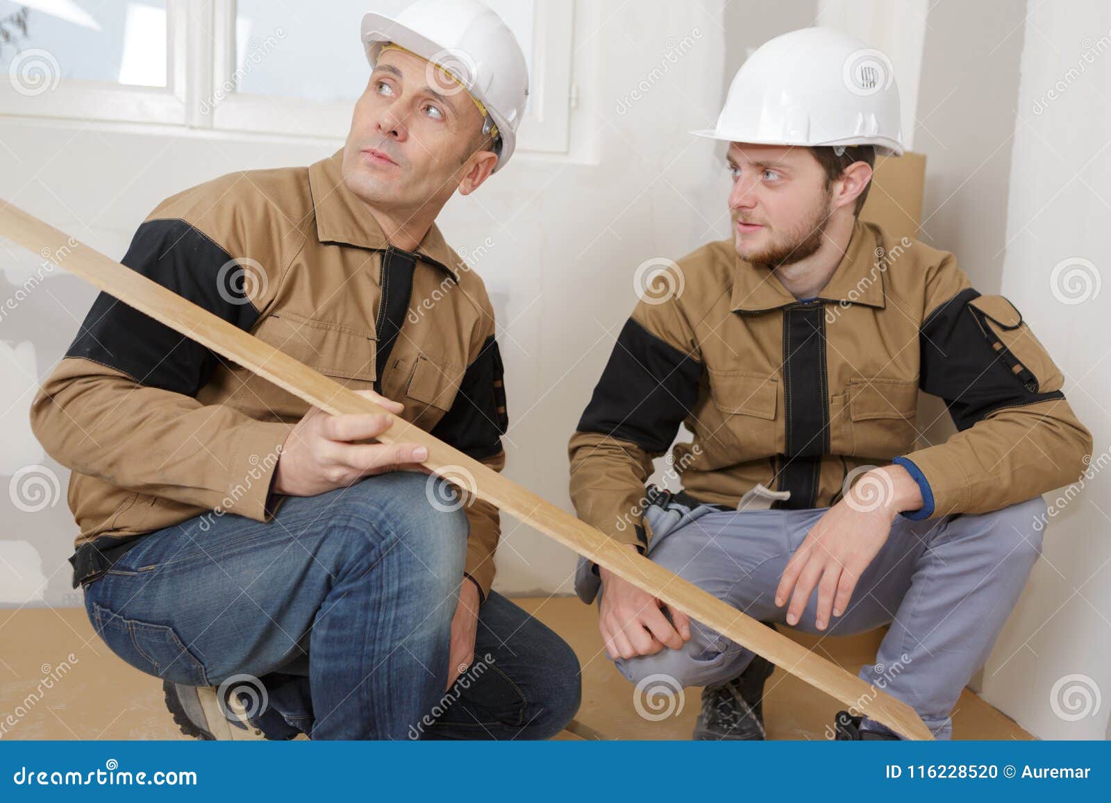 Workmen Crouching Looking at Floorboard Stock Photo - Image of hardhat ...