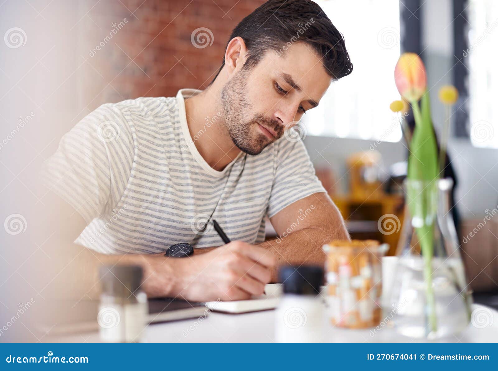 The Write Stuff. Shot of a Handsome Young Man Writing in a Notebook ...
