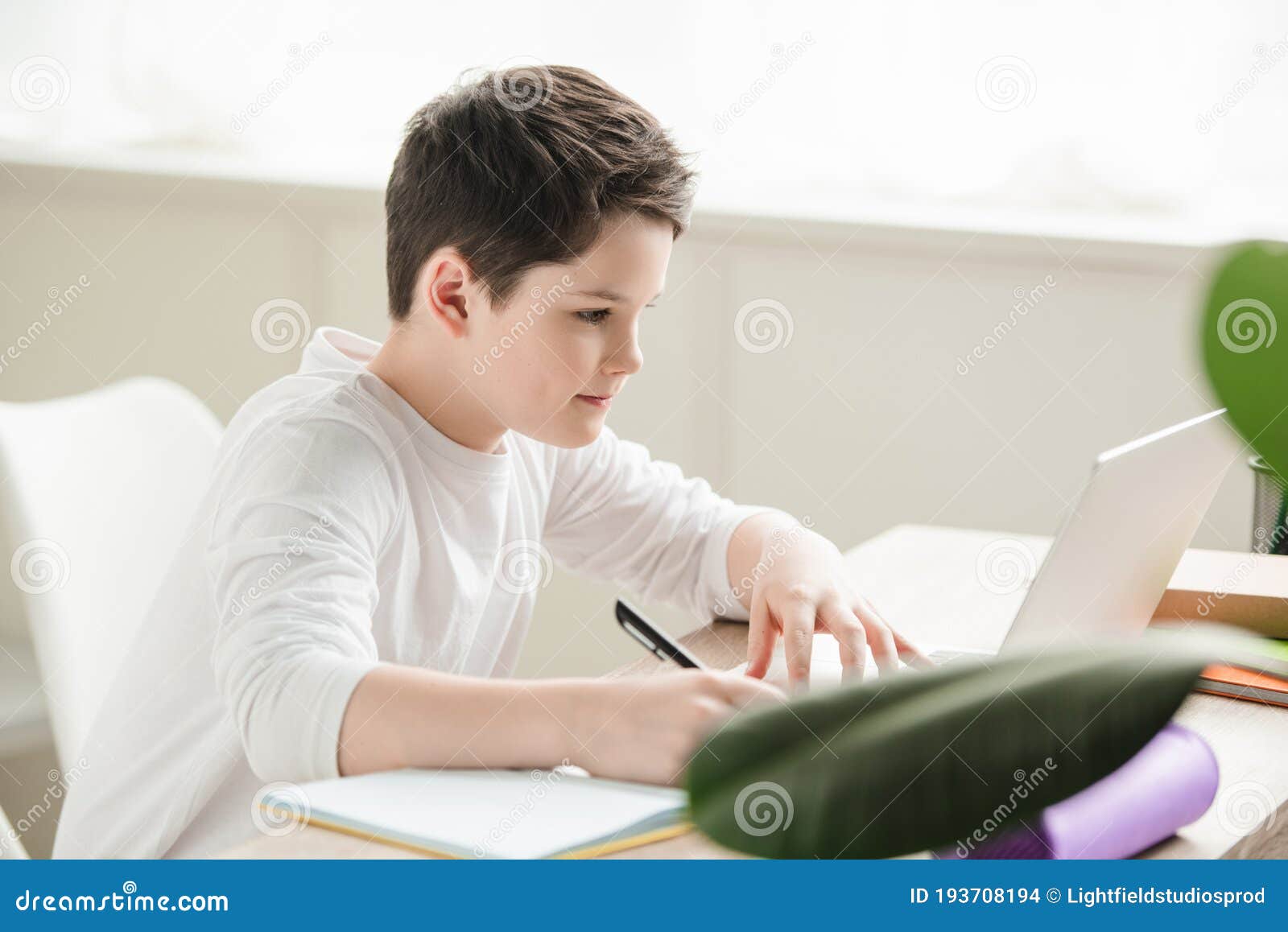 Writing in Notebook and Using Laptop while Doing Schoolwork at Home ...