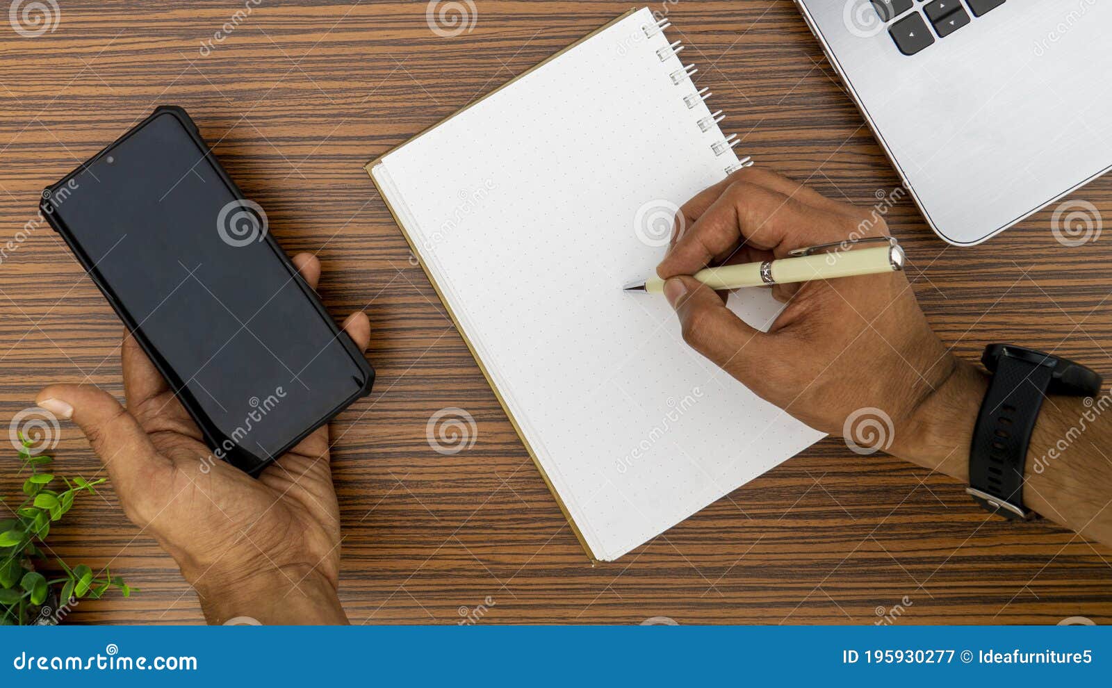 Writing on a Notepad while Holding a Mobile Phone Working in an Office ...