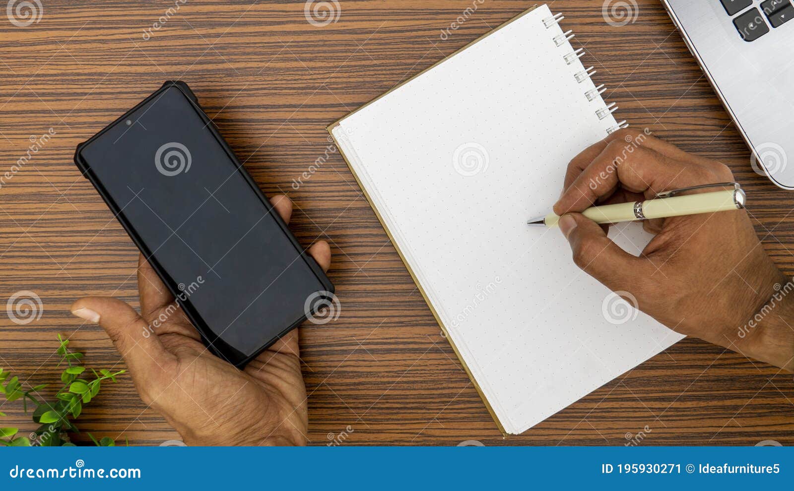 Writing on a Notepad while Holding a Mobile Phone Working in an Office ...