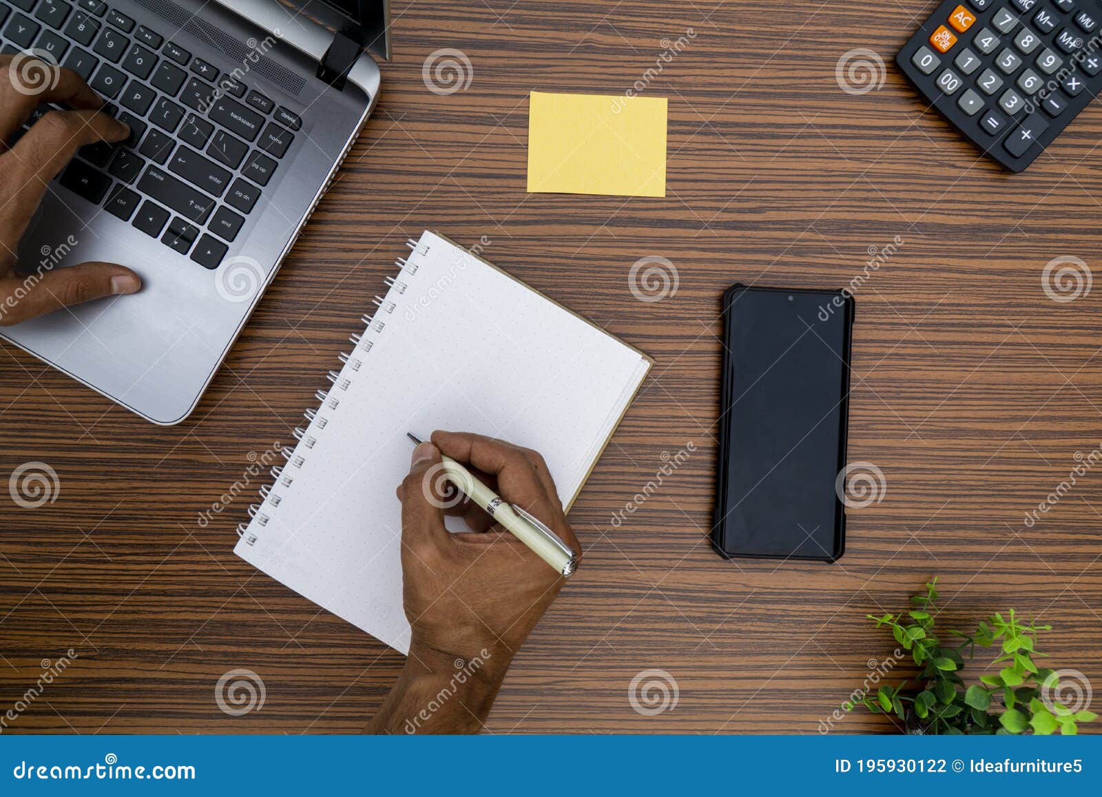 Writing on a Notepad and Typing on a Keyboard while Working on a ...