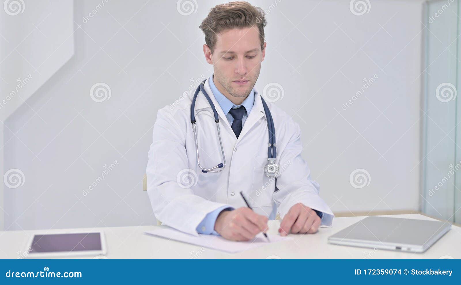 Writing Young Doctor Doing Paperwork in Clinic Stock Photo - Image of ...