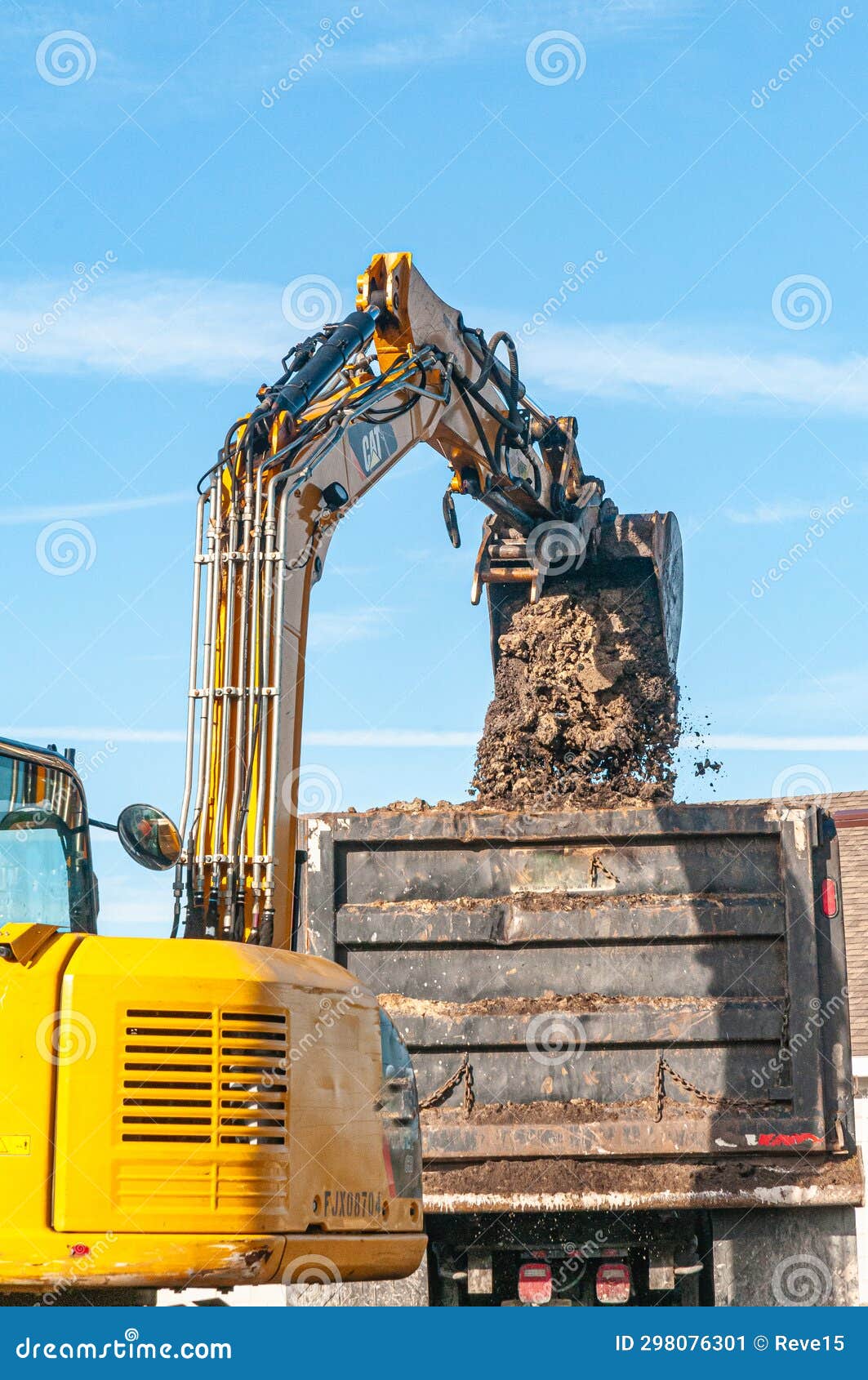 A 4x4 Backhoe Loader, Dumping Dirt into a Commercial Dump Truck Stock ...