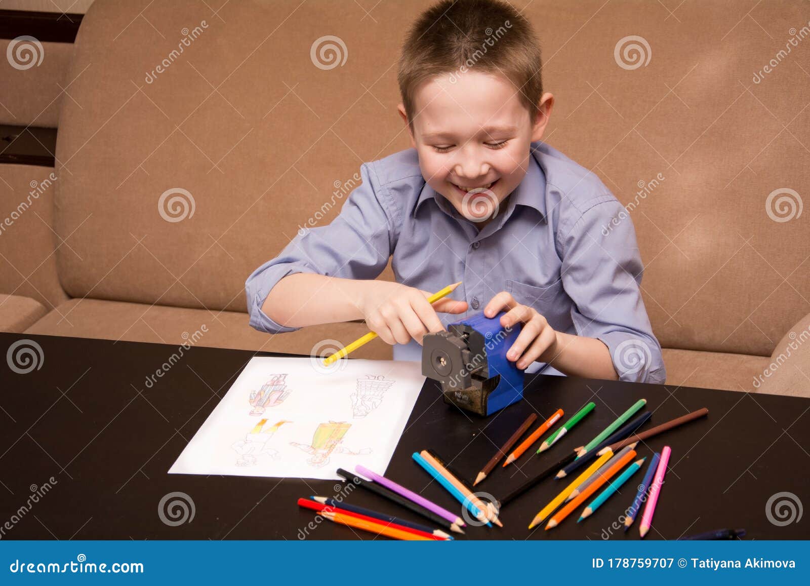 A 6-7 Year-old Boy Sharpens Pencils in a Sharpener, Sitting at a Black ...