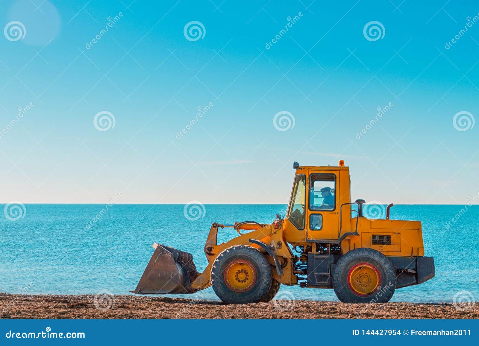 Yellow Bulldozer on the Background of Clear Blue Sky and Sea. Copy ...