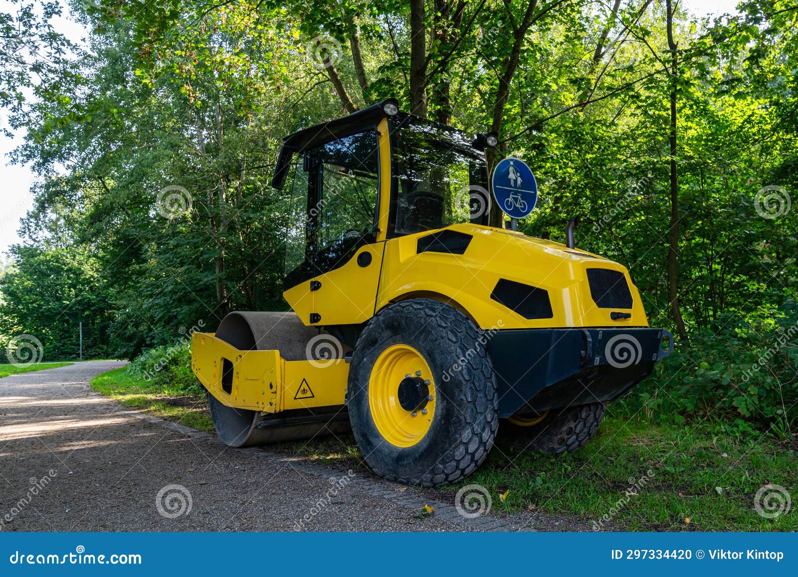 A Yellow Construction Roller Standing on the Side of a Path in the Park ...