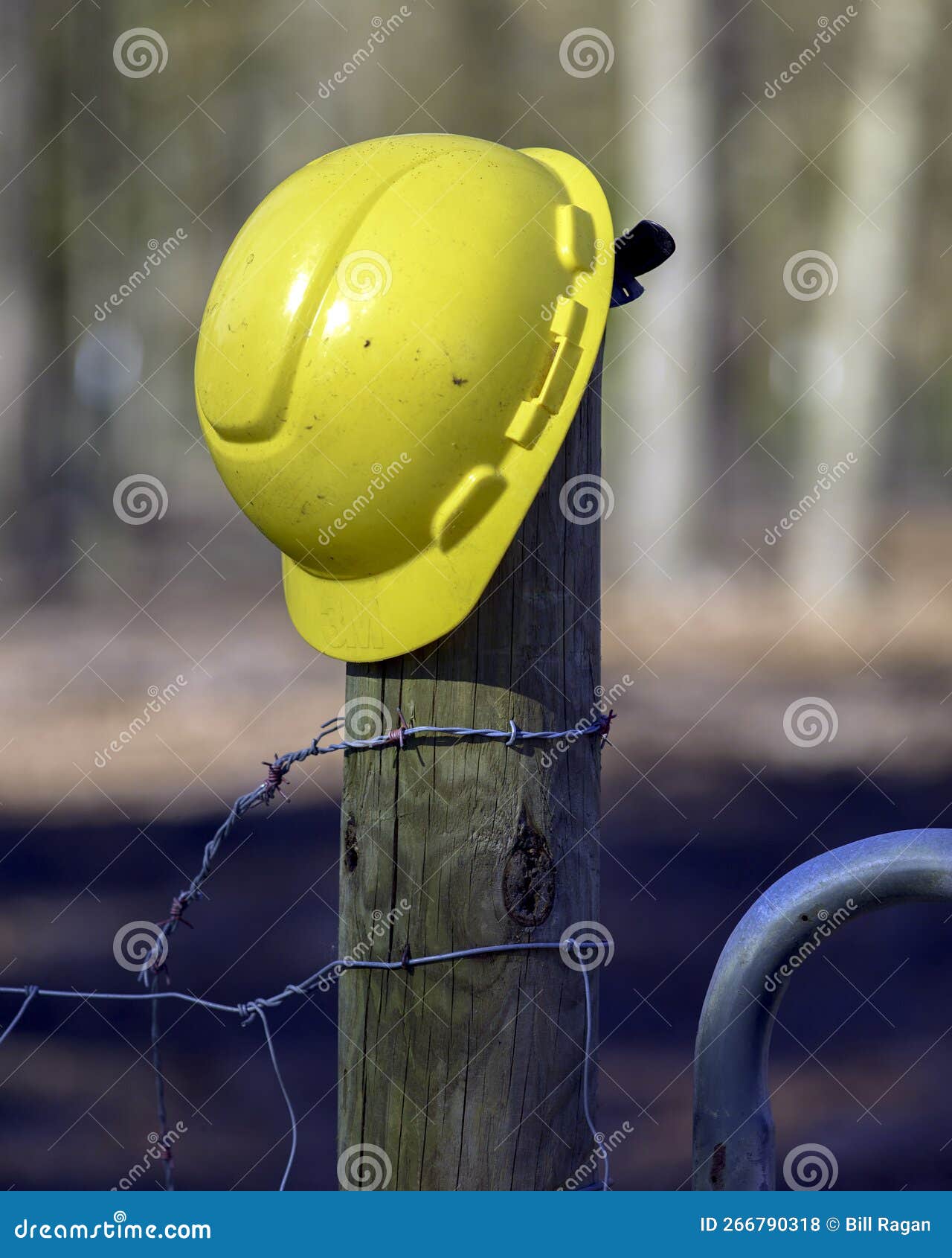 A Yellow Construction Workers Helmet Next To a Fence and Barbed Wire ...